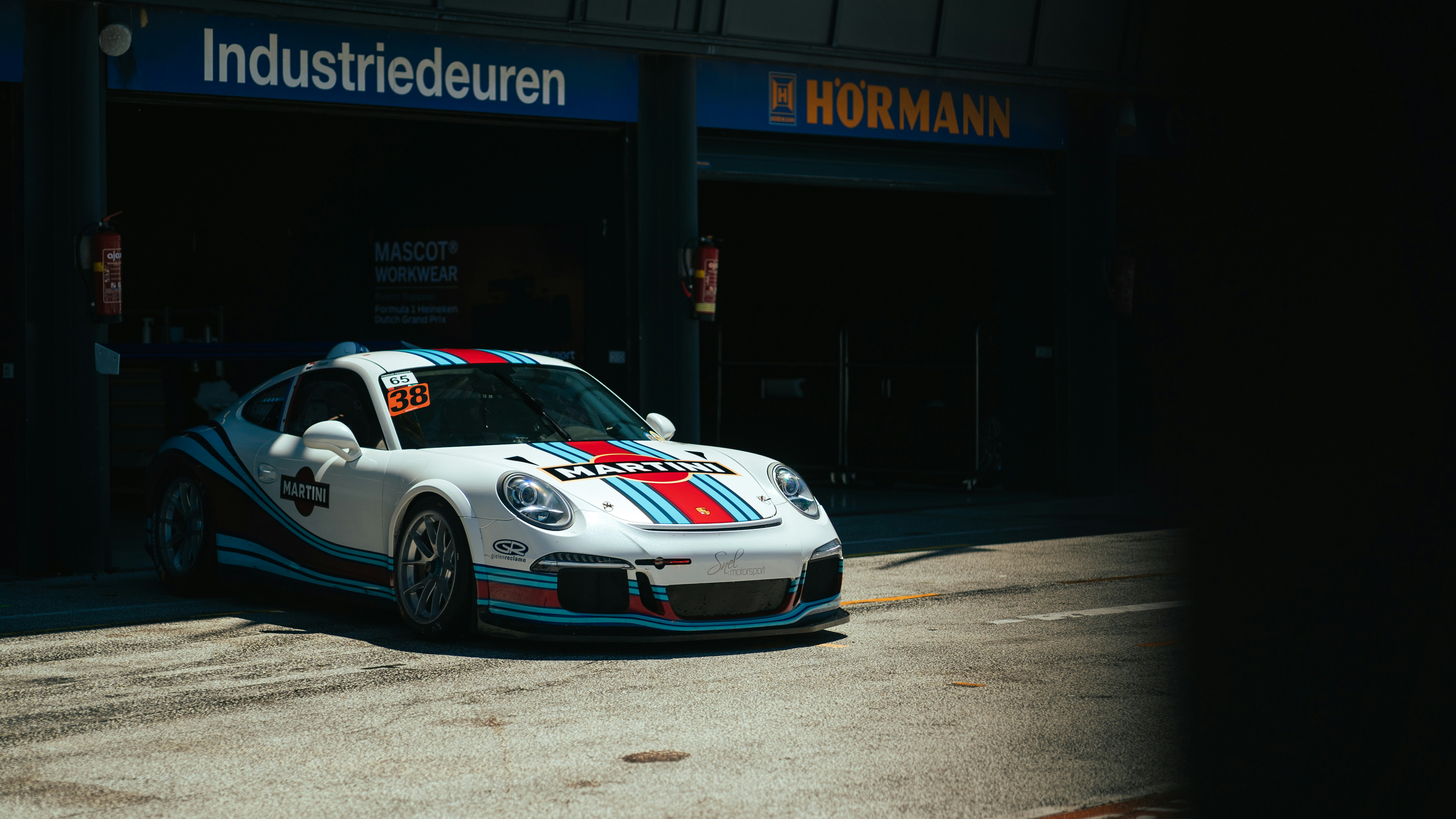 Martini-striped Porsche 911 in a dim pit lane