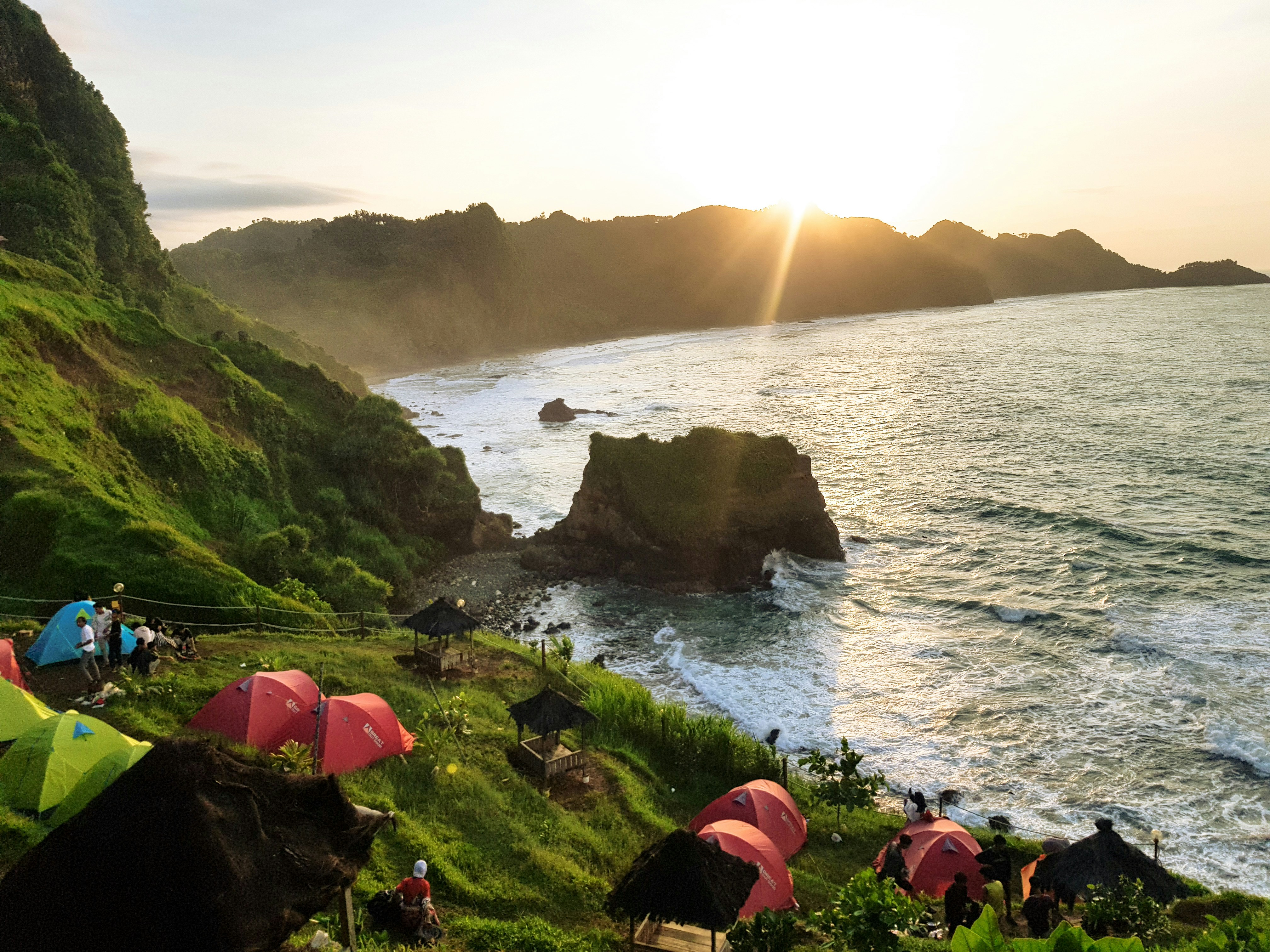 Sunlit Cliffside Campsite Overlooking a Surfing Shore