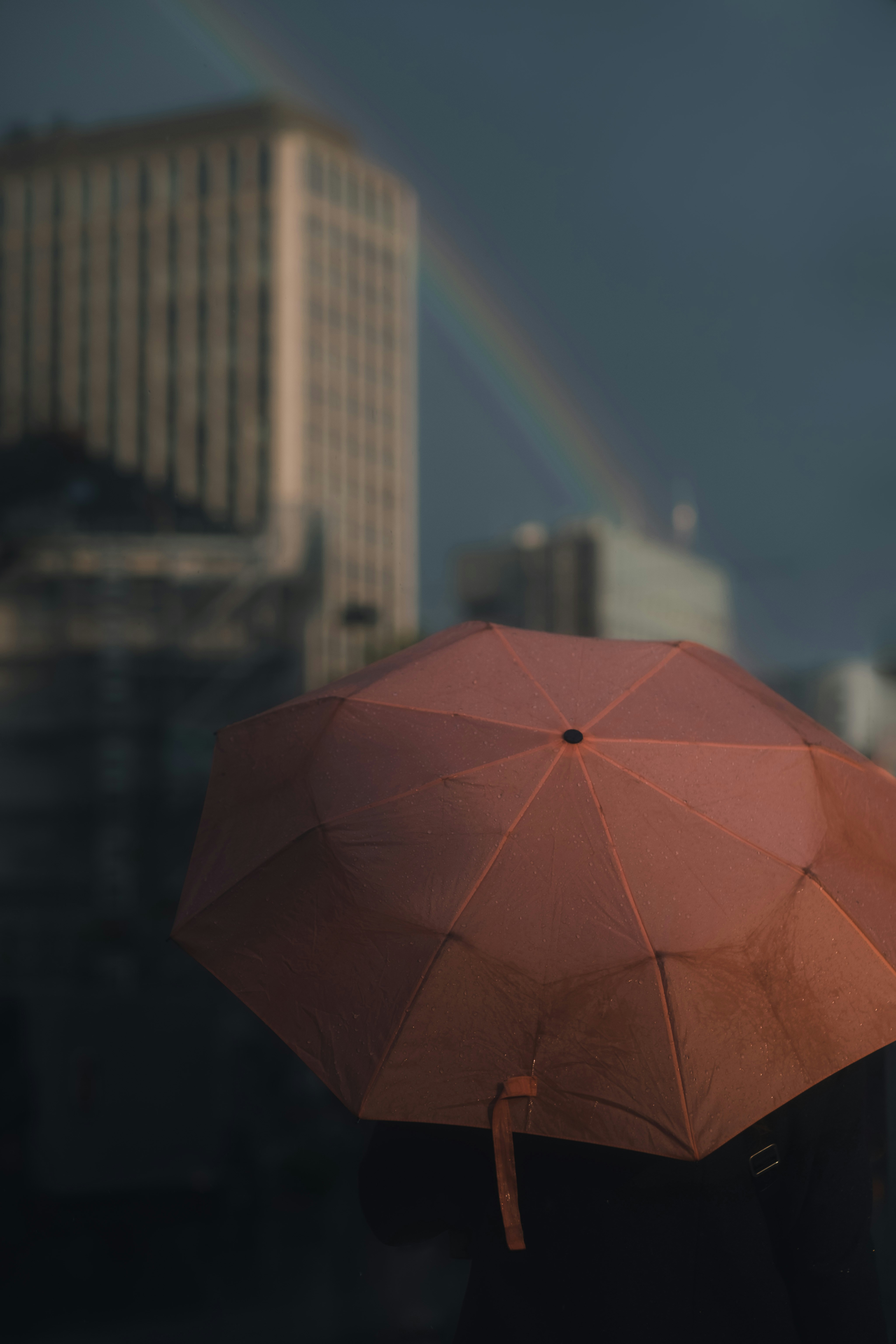 Umbrella in front of rainbow.
