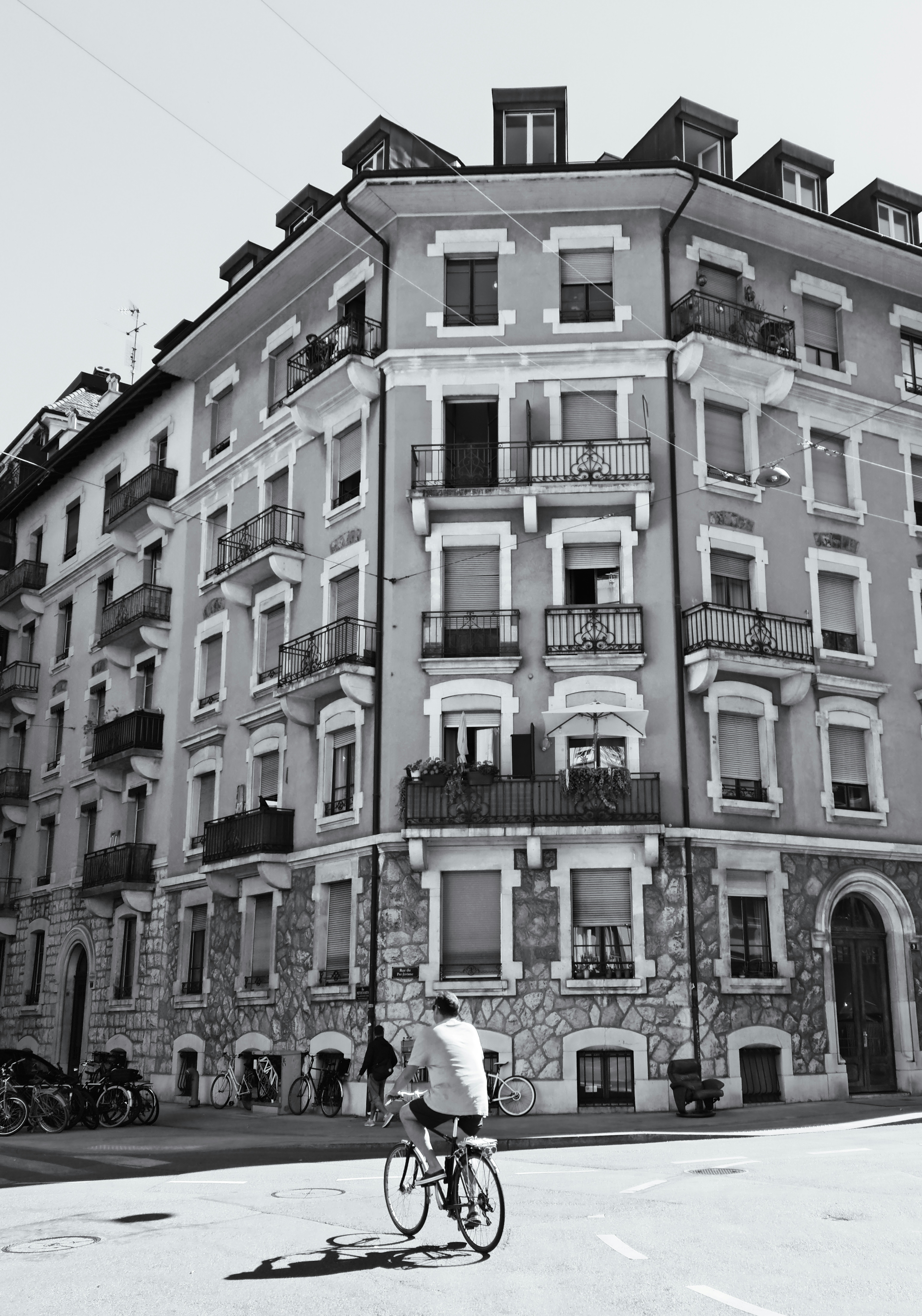 Monochrome Cornerstone: A Cyclist Traces the Lines of a Parisian Façade