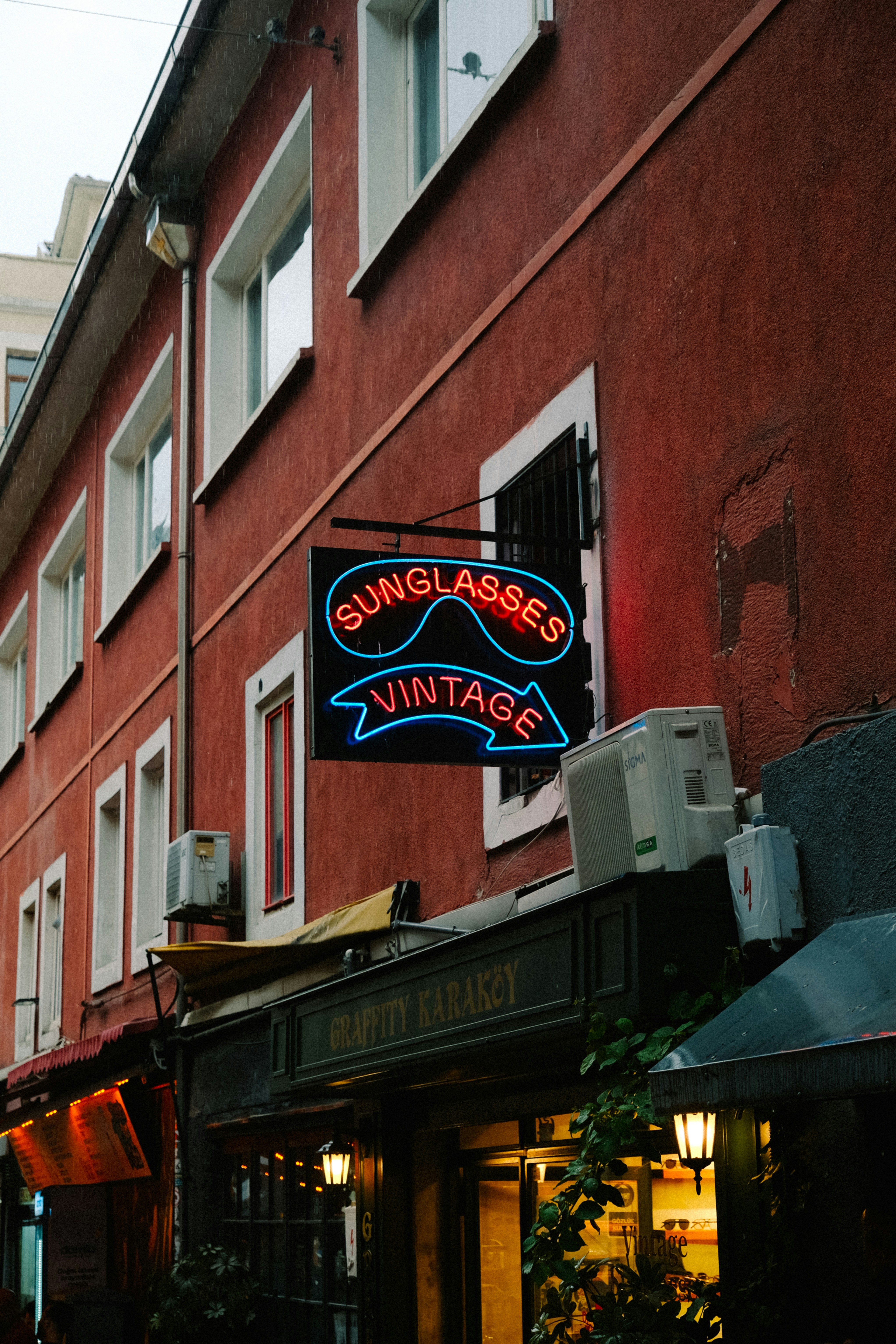 Neon Serenade for Vintage Sunglasses on a Red Brick Facade