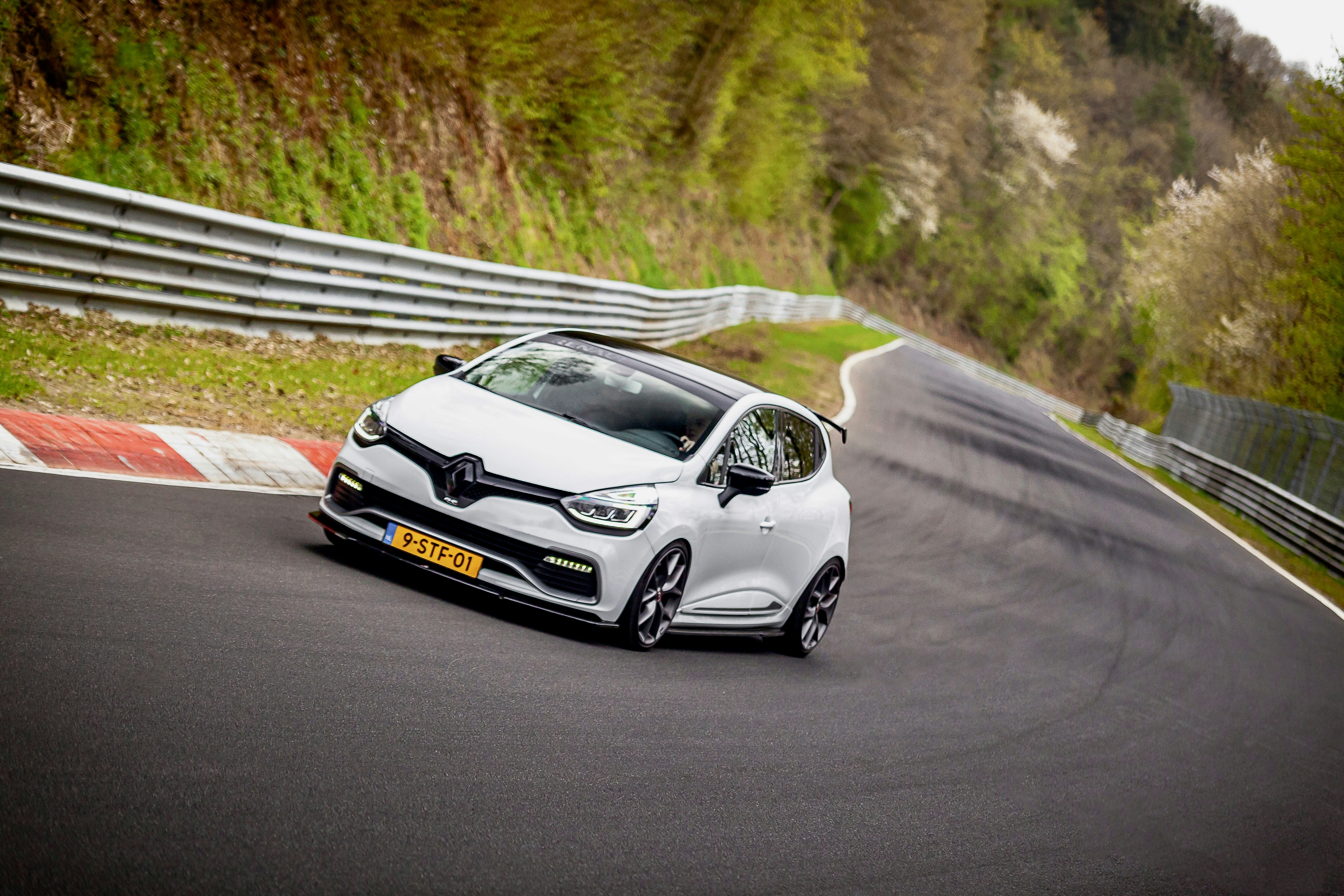 White Renault dances through a forested chicane on a winding track