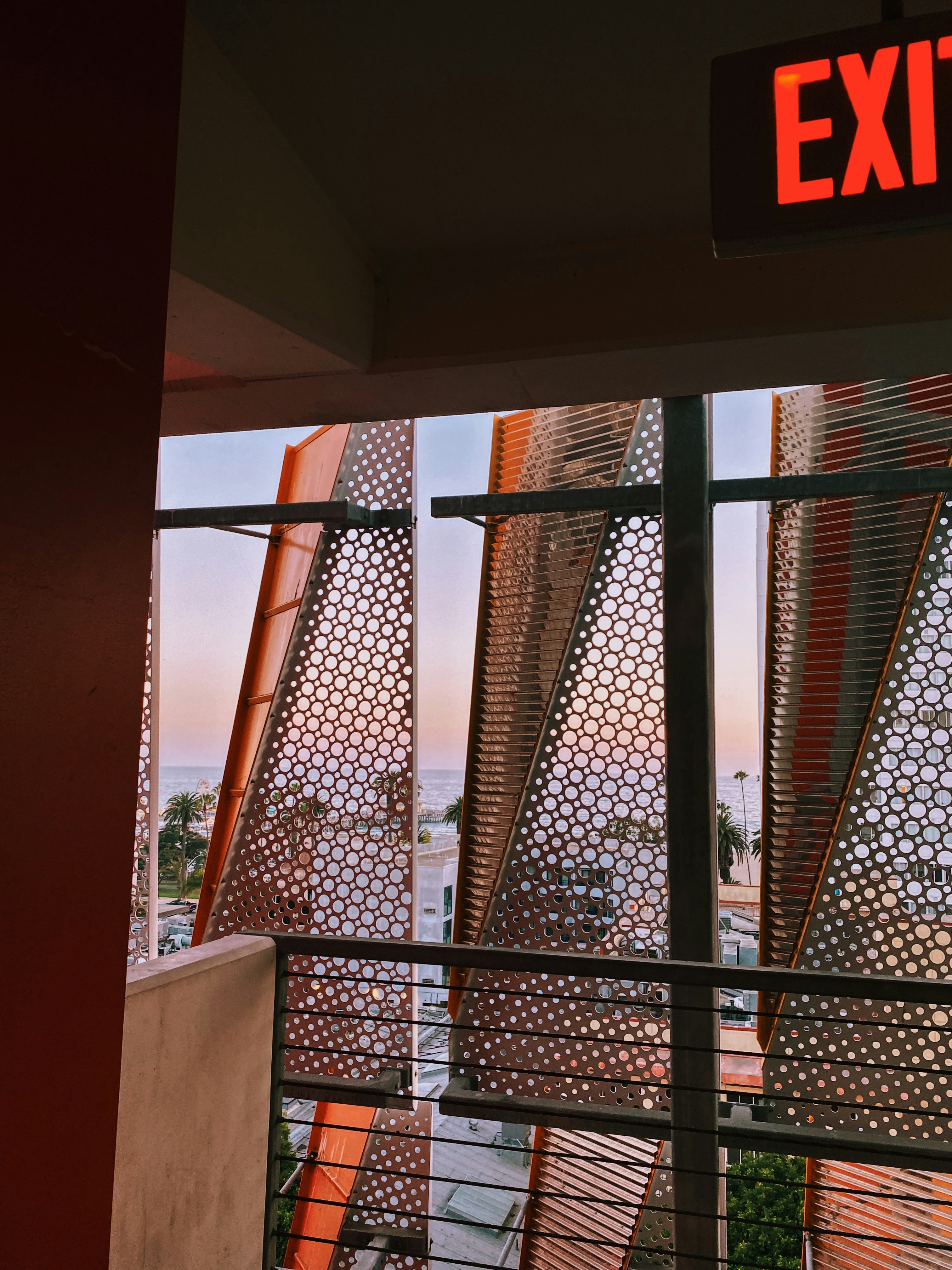 Orange Perforated Ribs Framing a Distant Palm Horizon