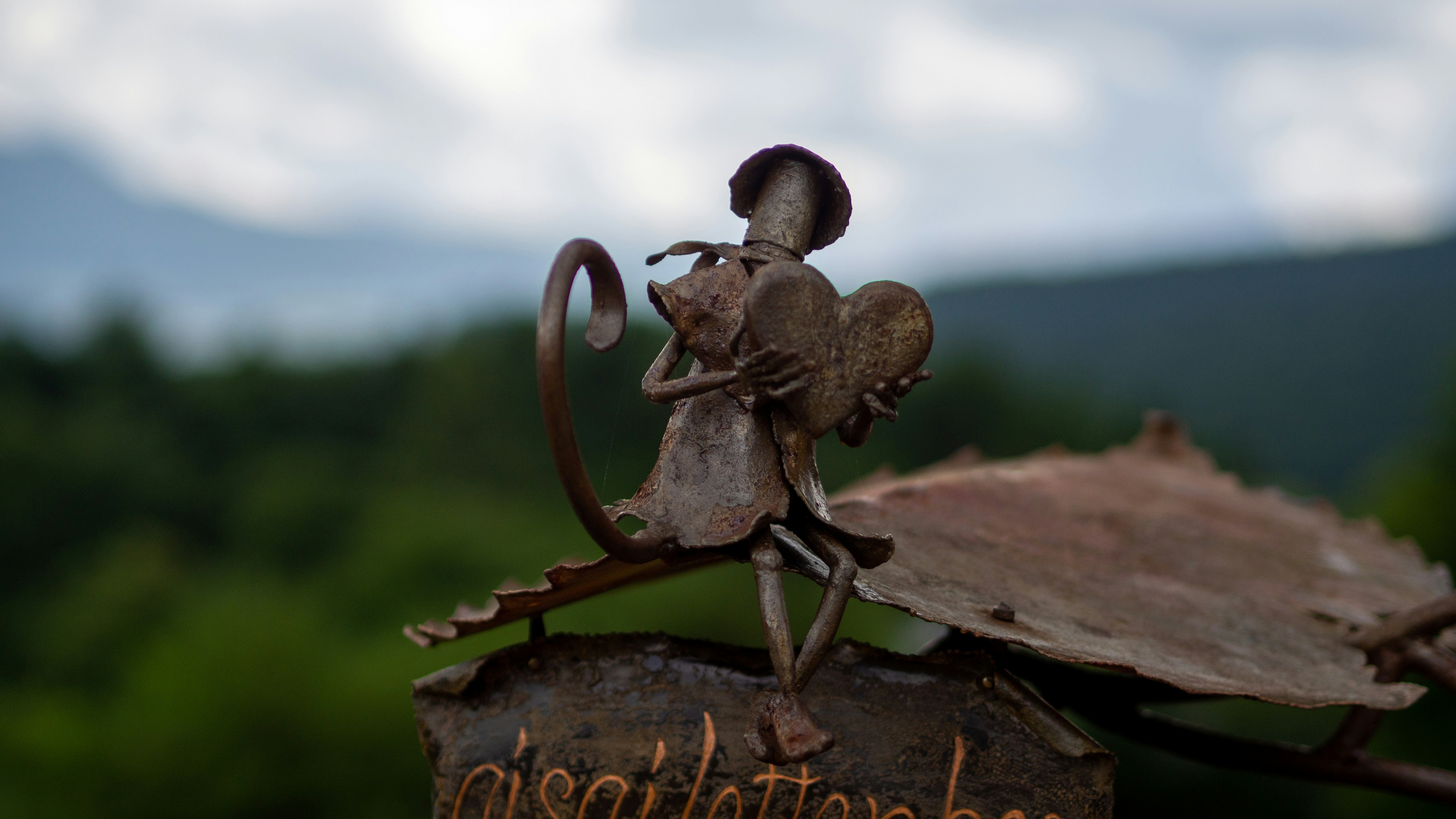 Tiny Guardian on a Worn Leaf: A Rusted Angel in Quiet Mountain Light