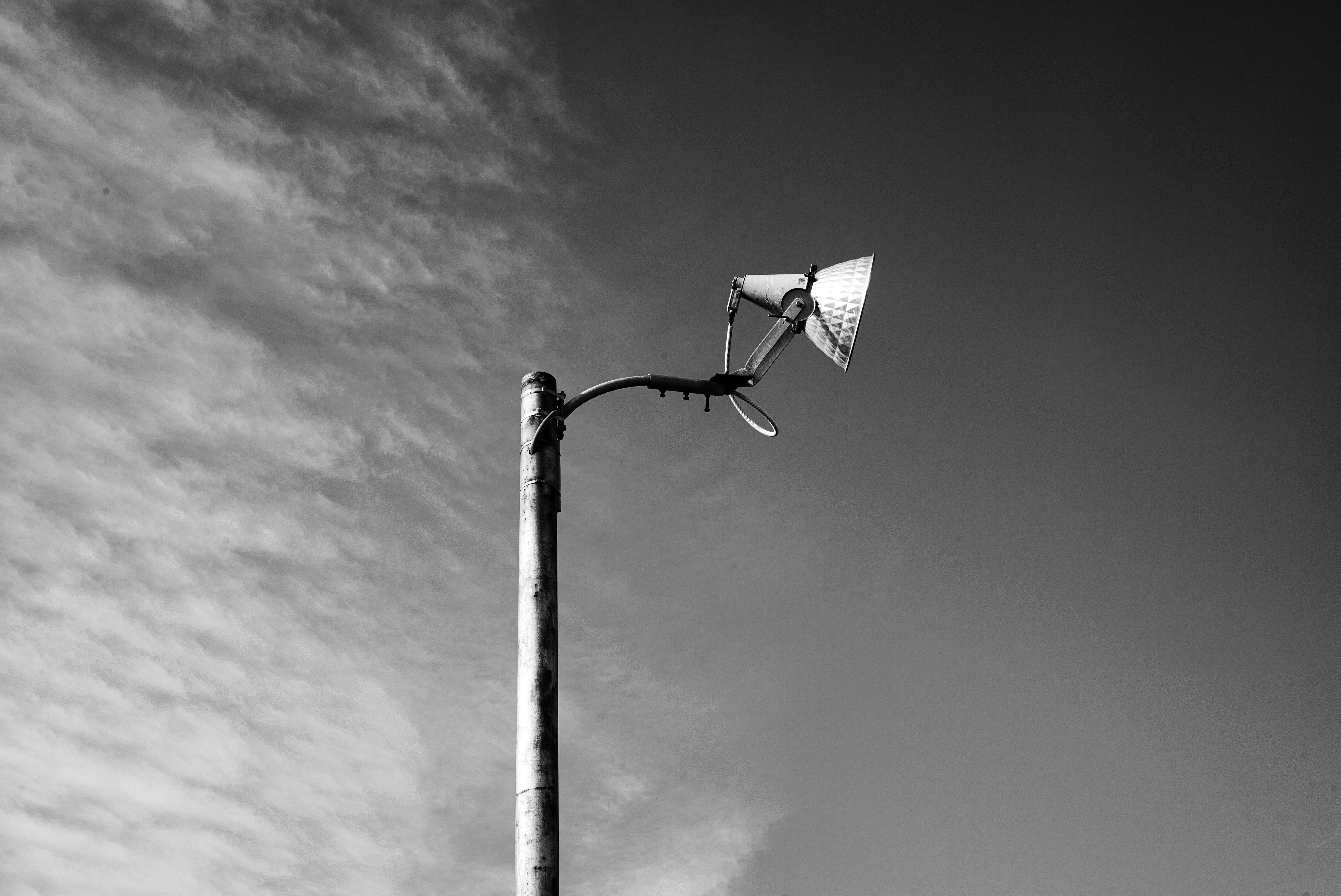 An old light sits fixed on a pole with clouds coming in from behind.
