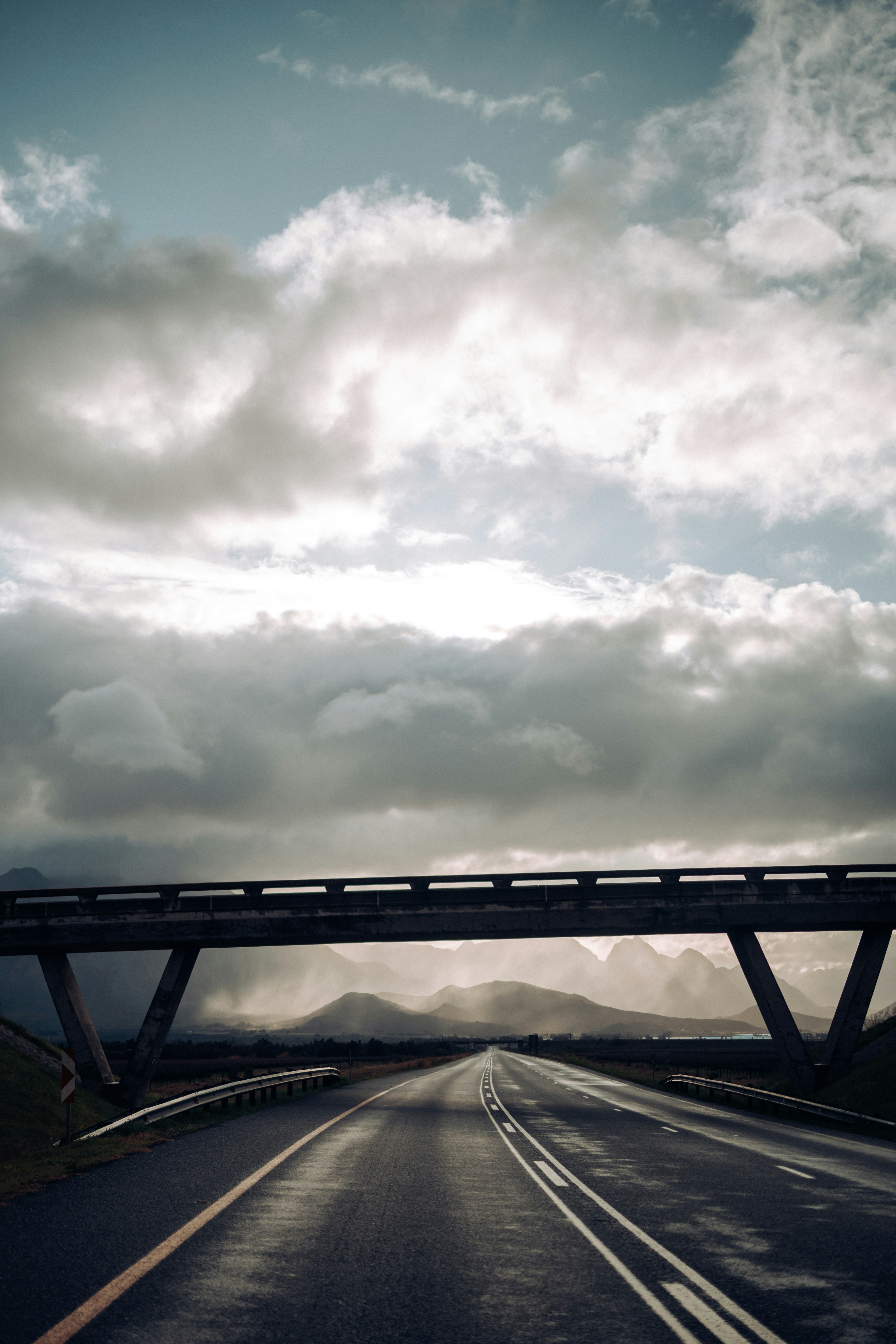 Vanishing Point: Road toward Misty Peaks Under a Moody Sky