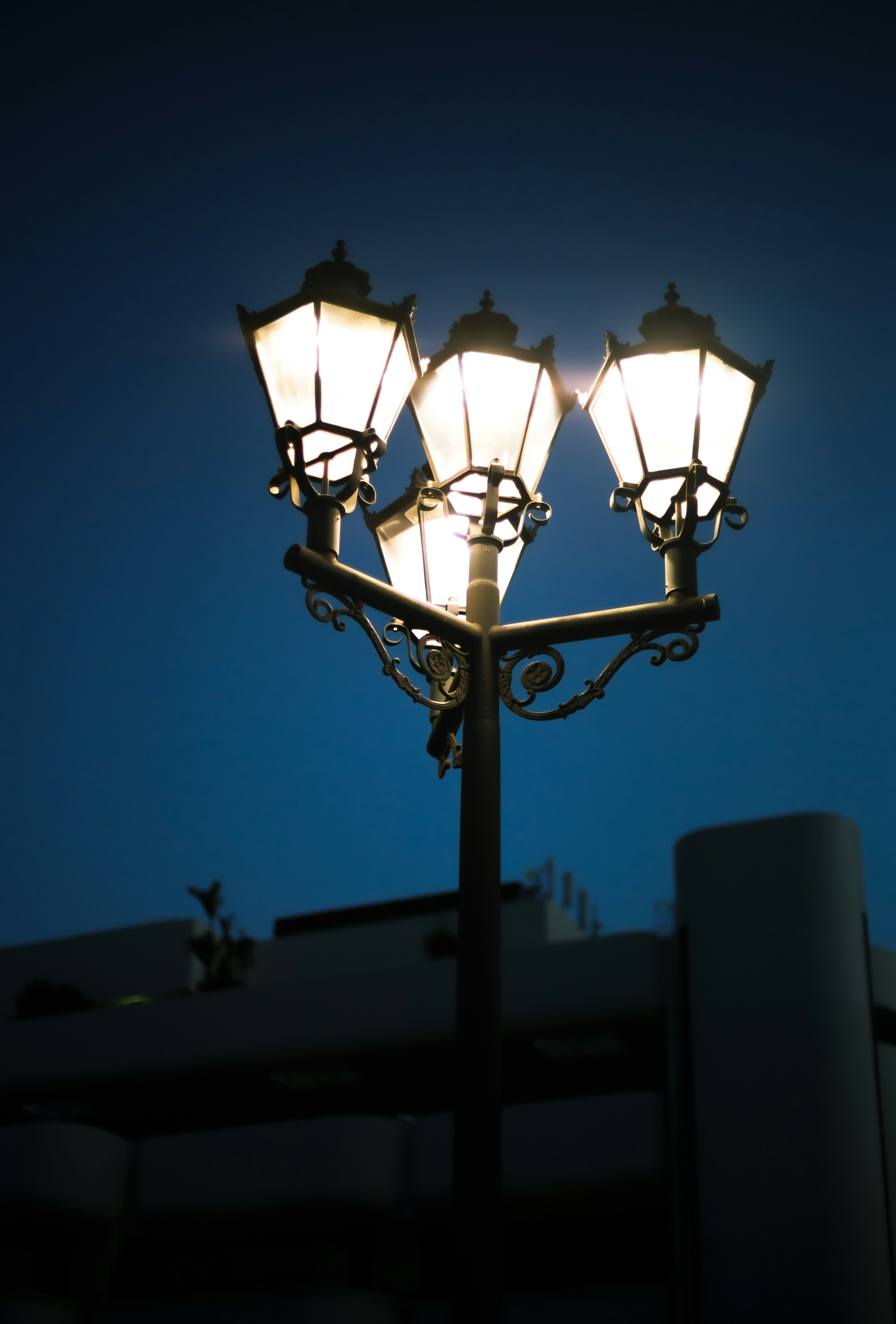 Four ornate street lamps glowing against a twilight backdrop, casting a warm light on the surroundings.