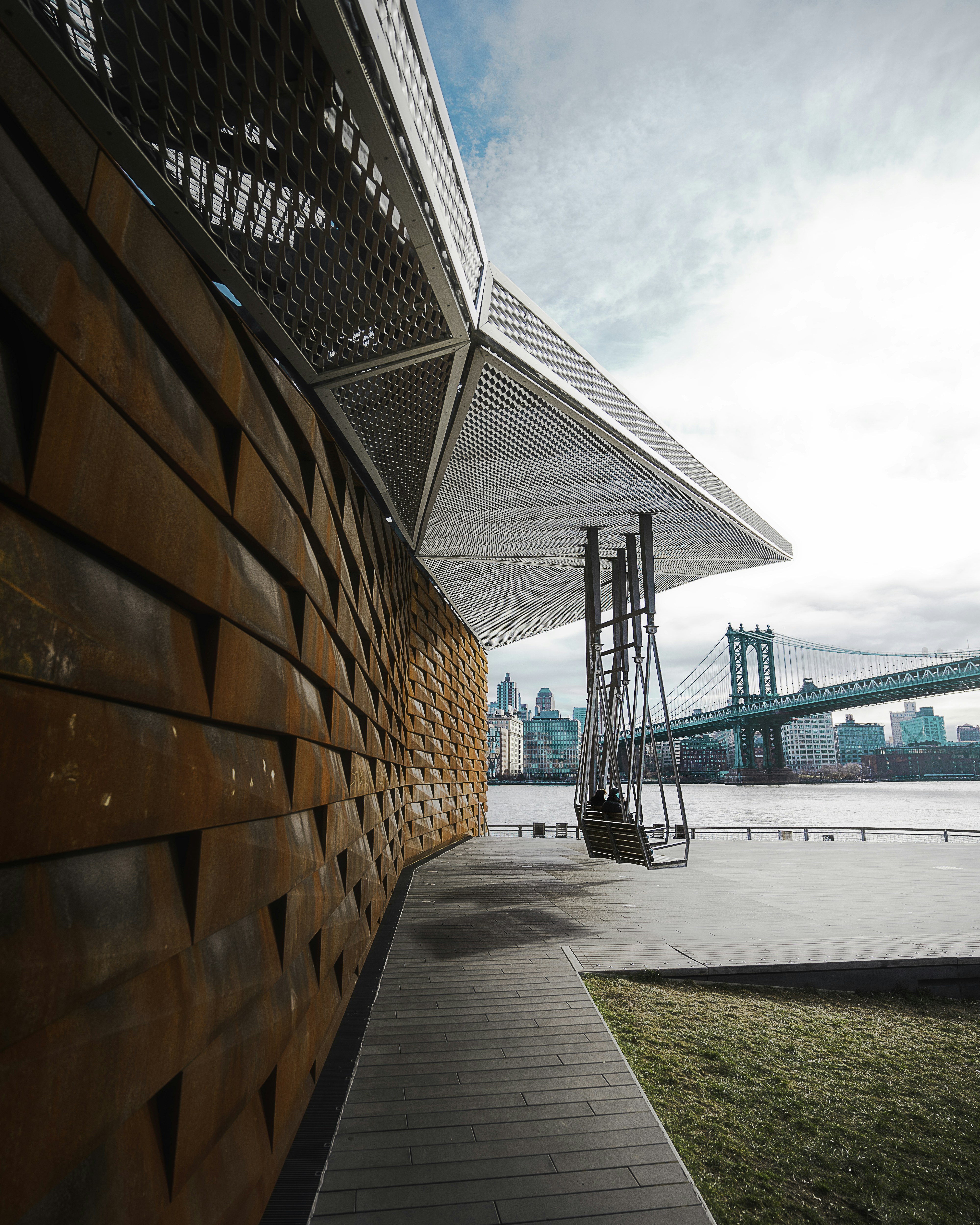 Riverside Canopy: Wood Facade, Steel Overhang, and a Distant Suspension Bridge