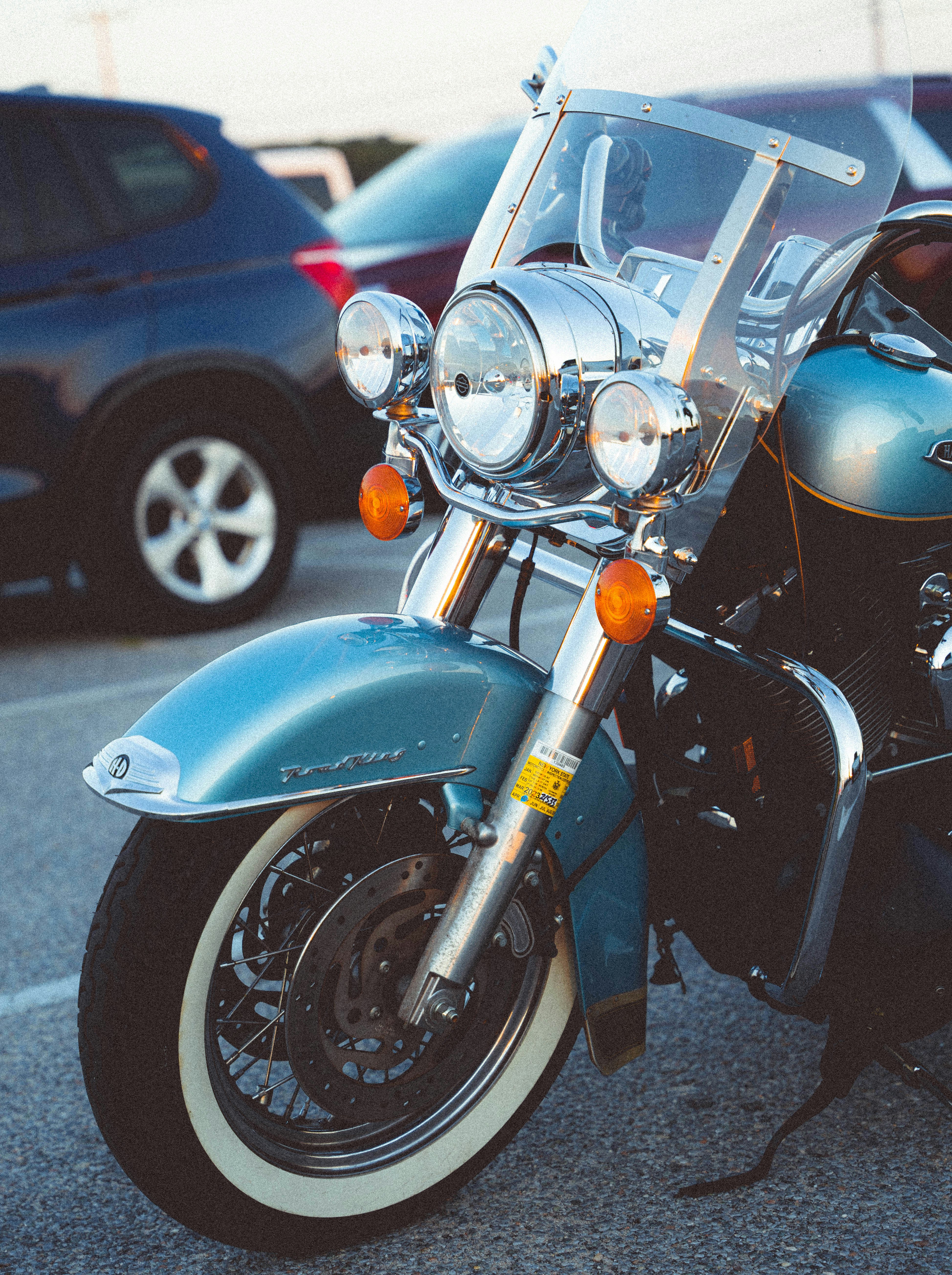 Close-up of a vintage motorcycle showcasing its chrome details and classic design elements. The bike is parked amidst modern vehicles.
