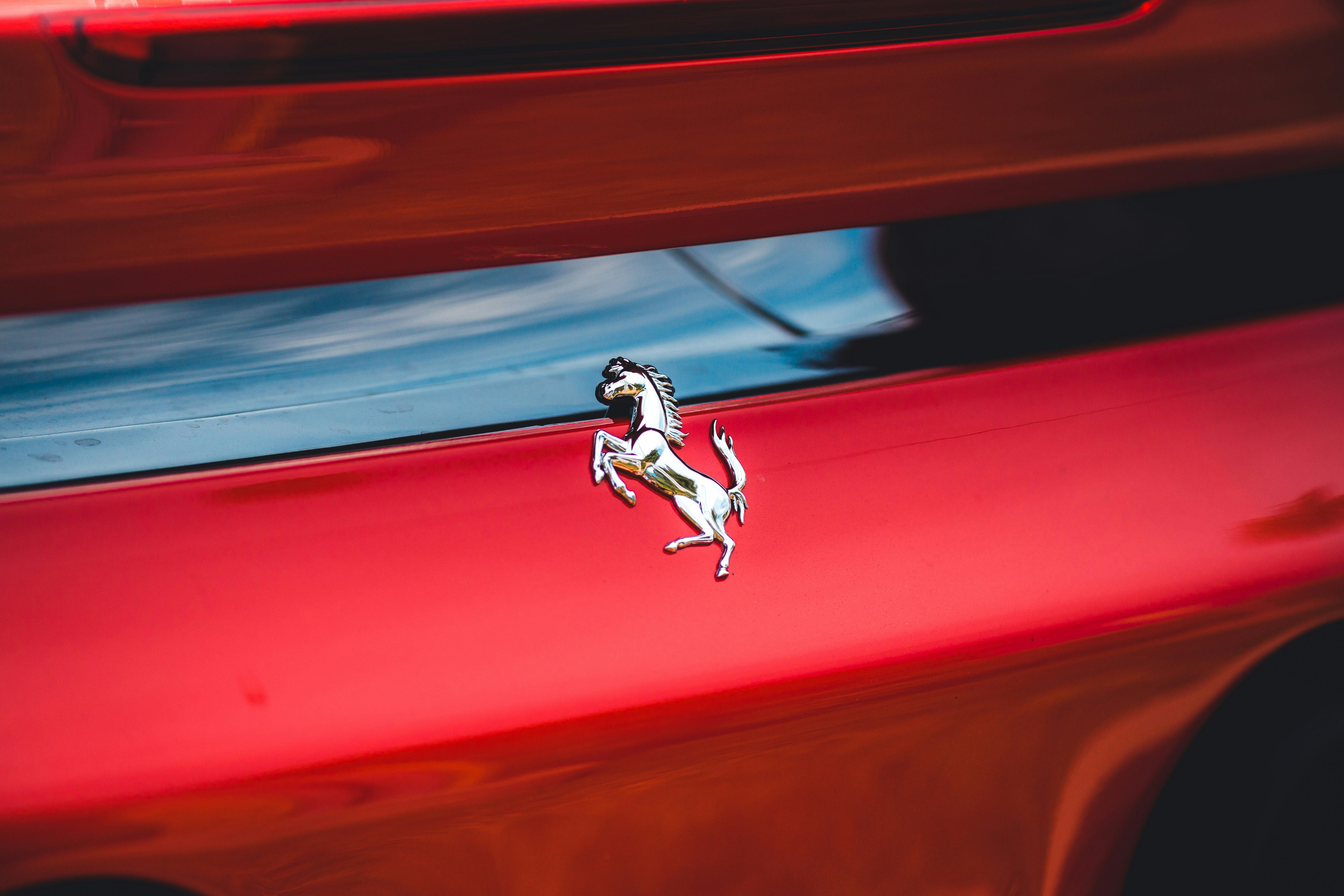 Ferrari logo prominently displayed on a glossy red car surface, reflecting light and showcasing its sleek design.