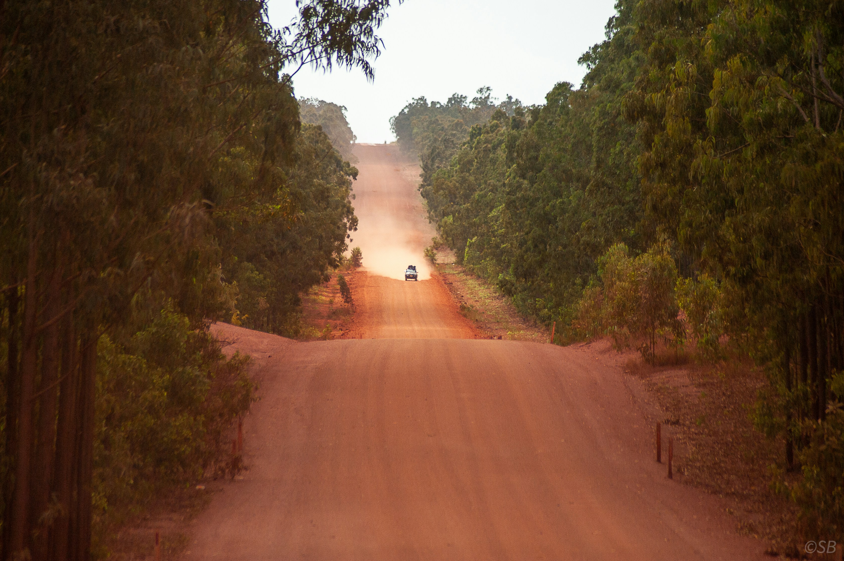 Dust Trail to the Distant Car on a Red Dirt Road