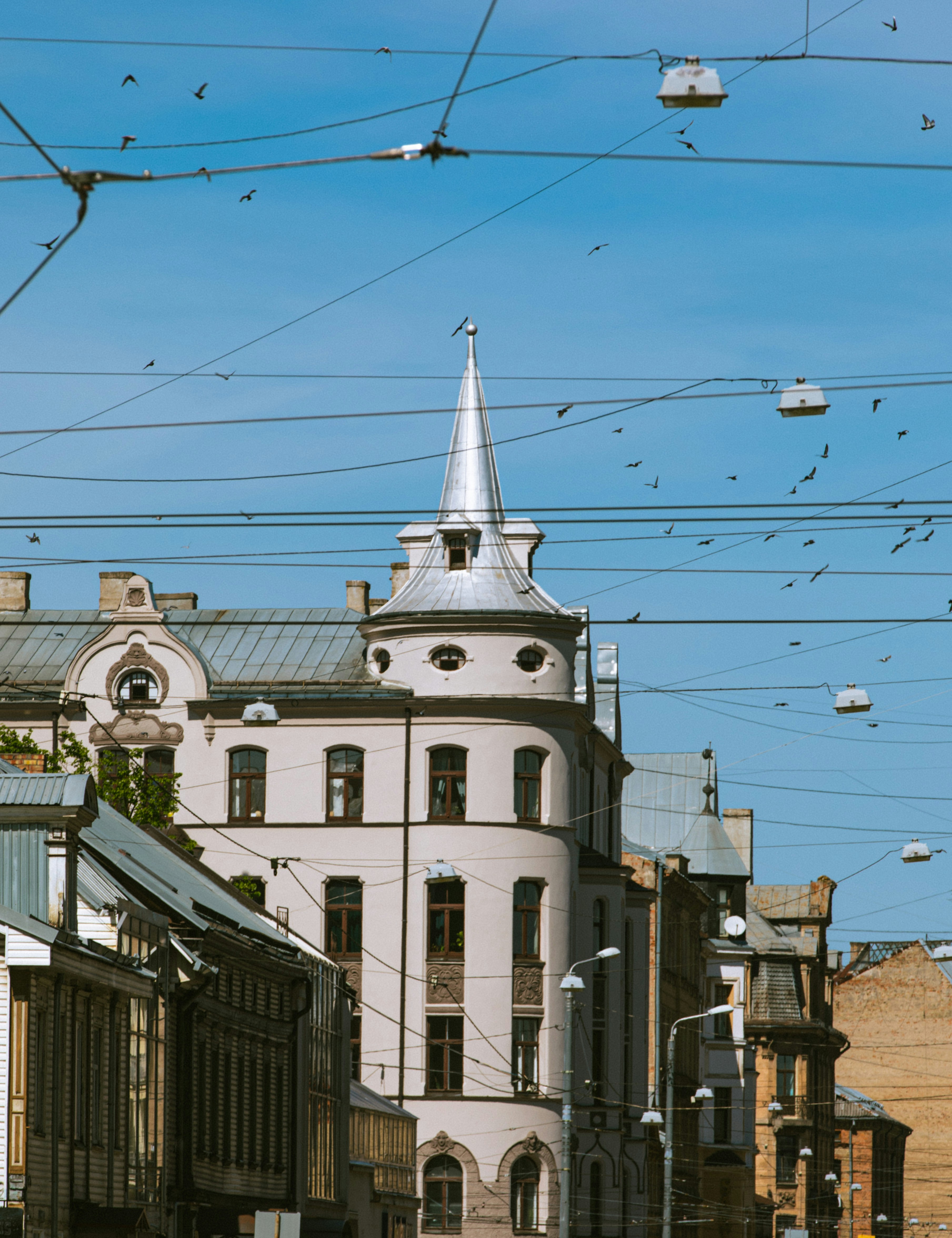 City tower beneath a web of tram cables against a blue sky