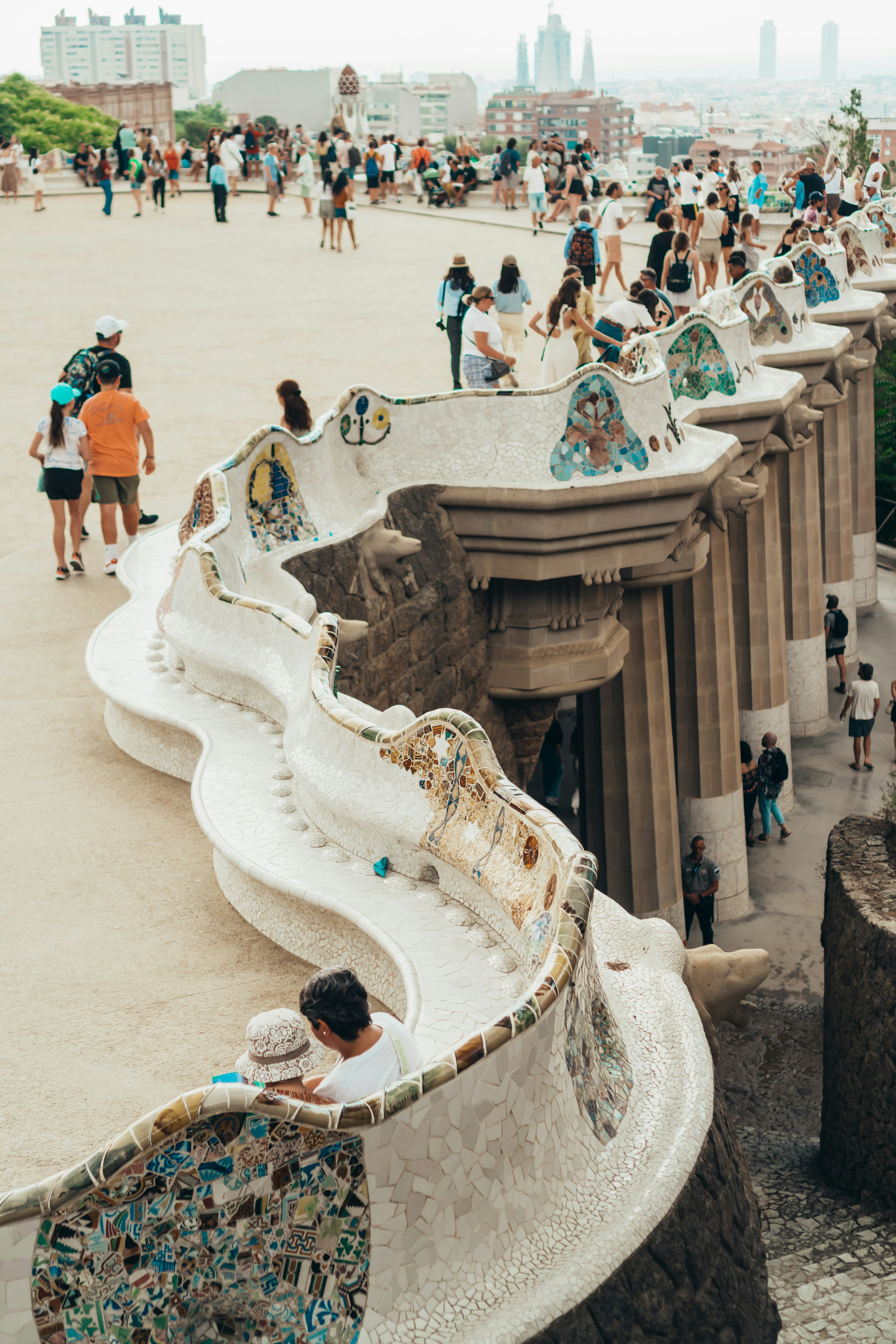 A serpentine mosaic path winds along the sunlit terrace, guiding visitors toward the distant cityscape