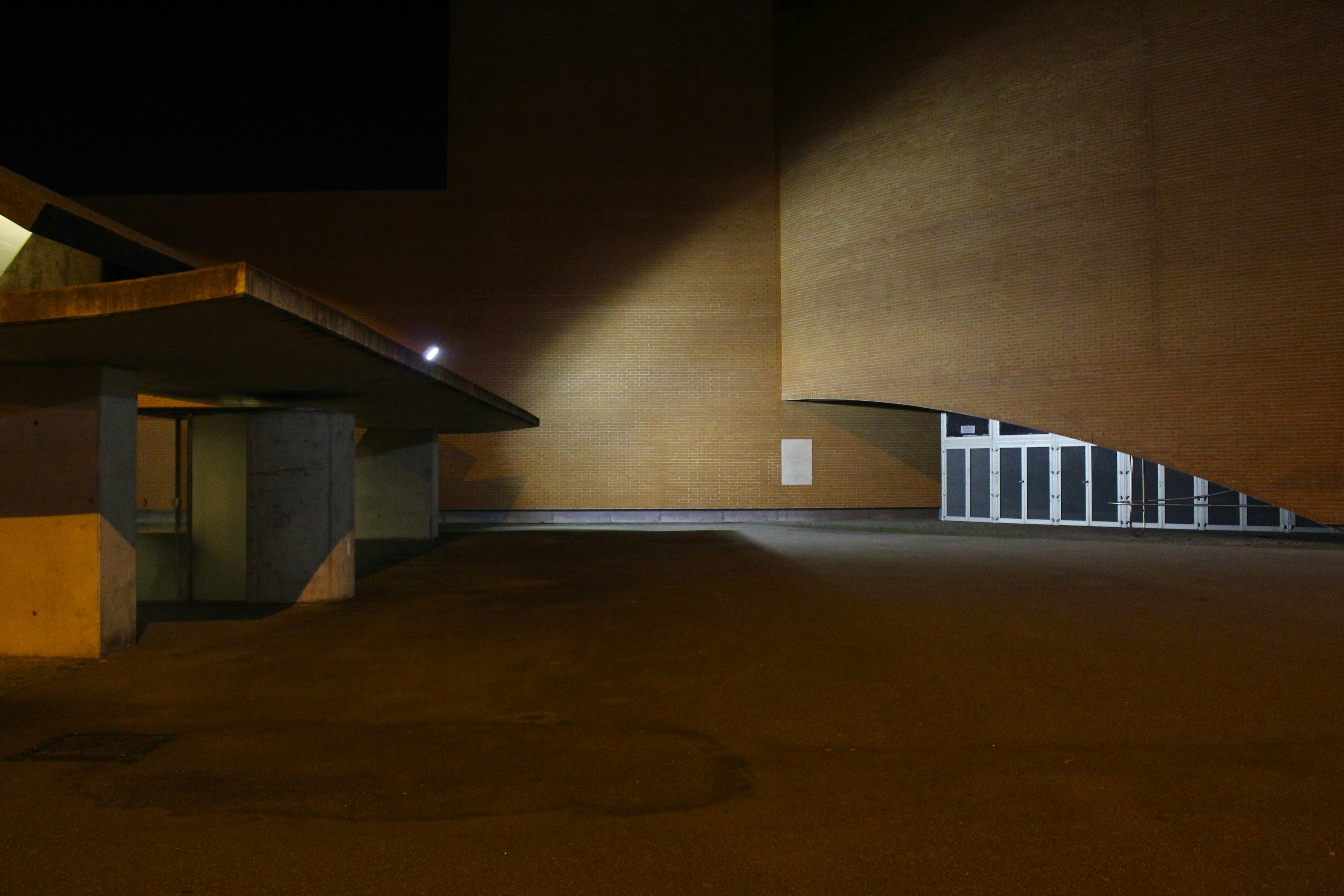 Modern architectural structure with dramatic lighting and shadows at night.