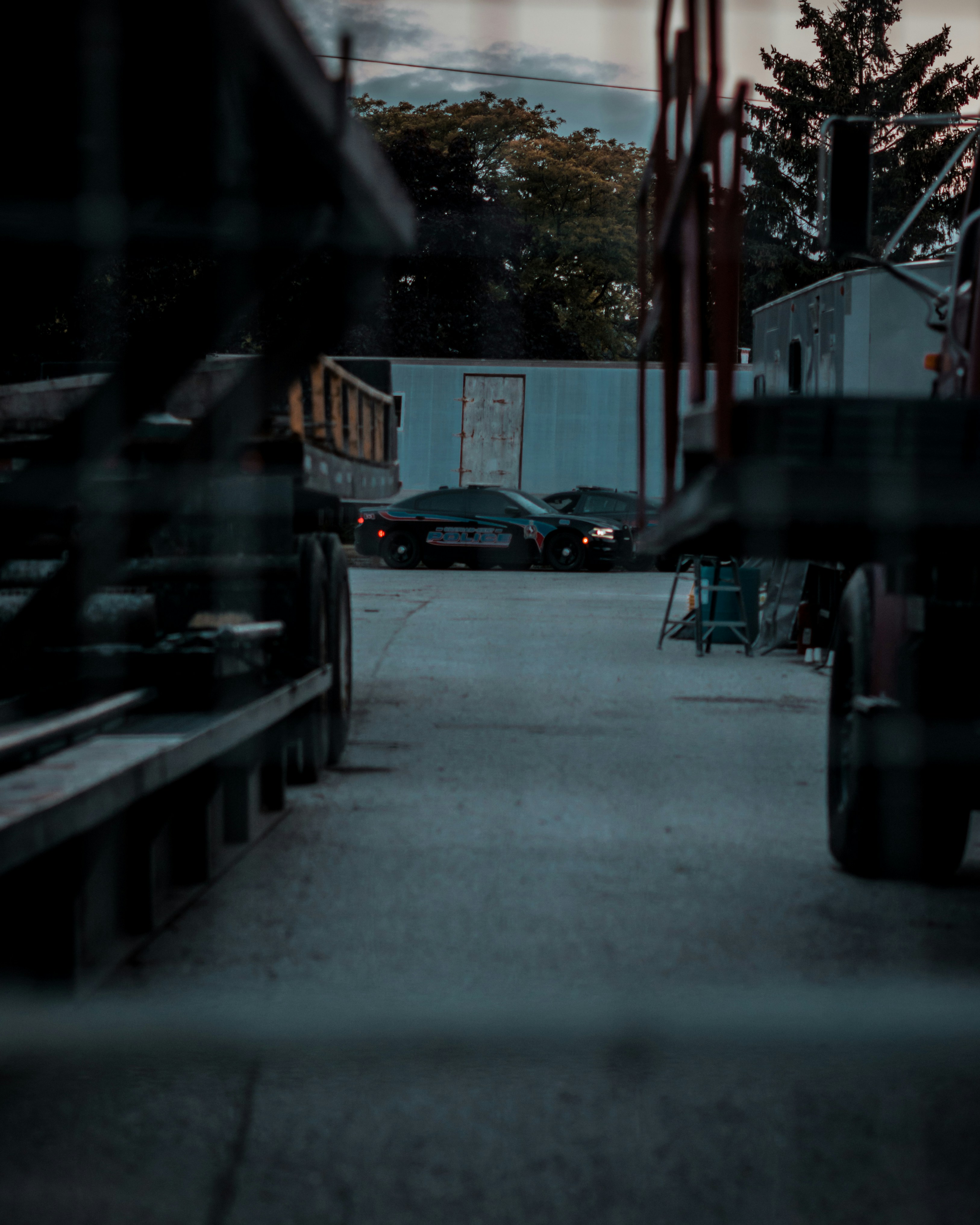 End of the Row: A Sleek Car Quietly Emerges Between Shadowed Trailers
