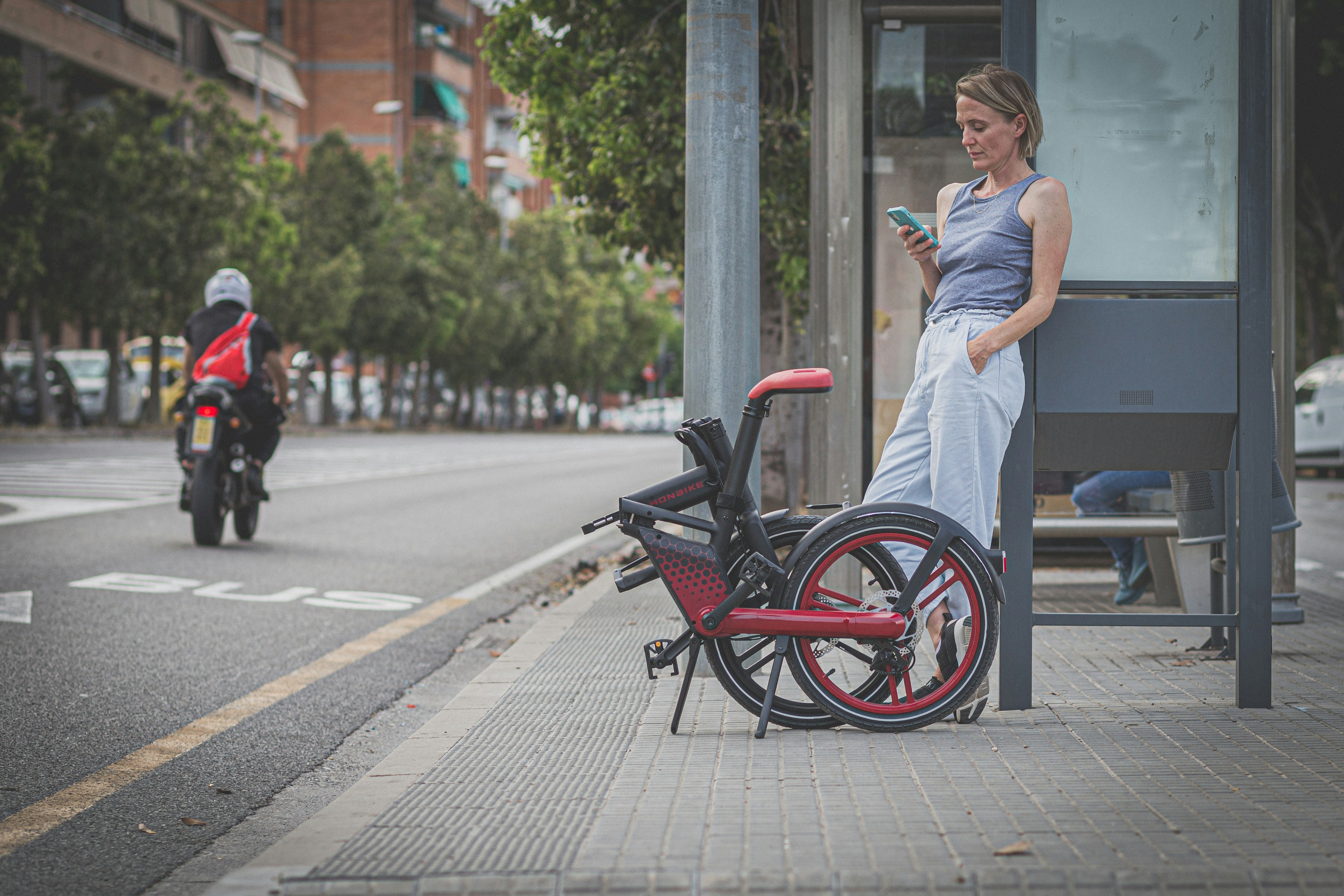 Urban Pause at the Stop: A Woman, a Red Bicycle, and a Quiet Street