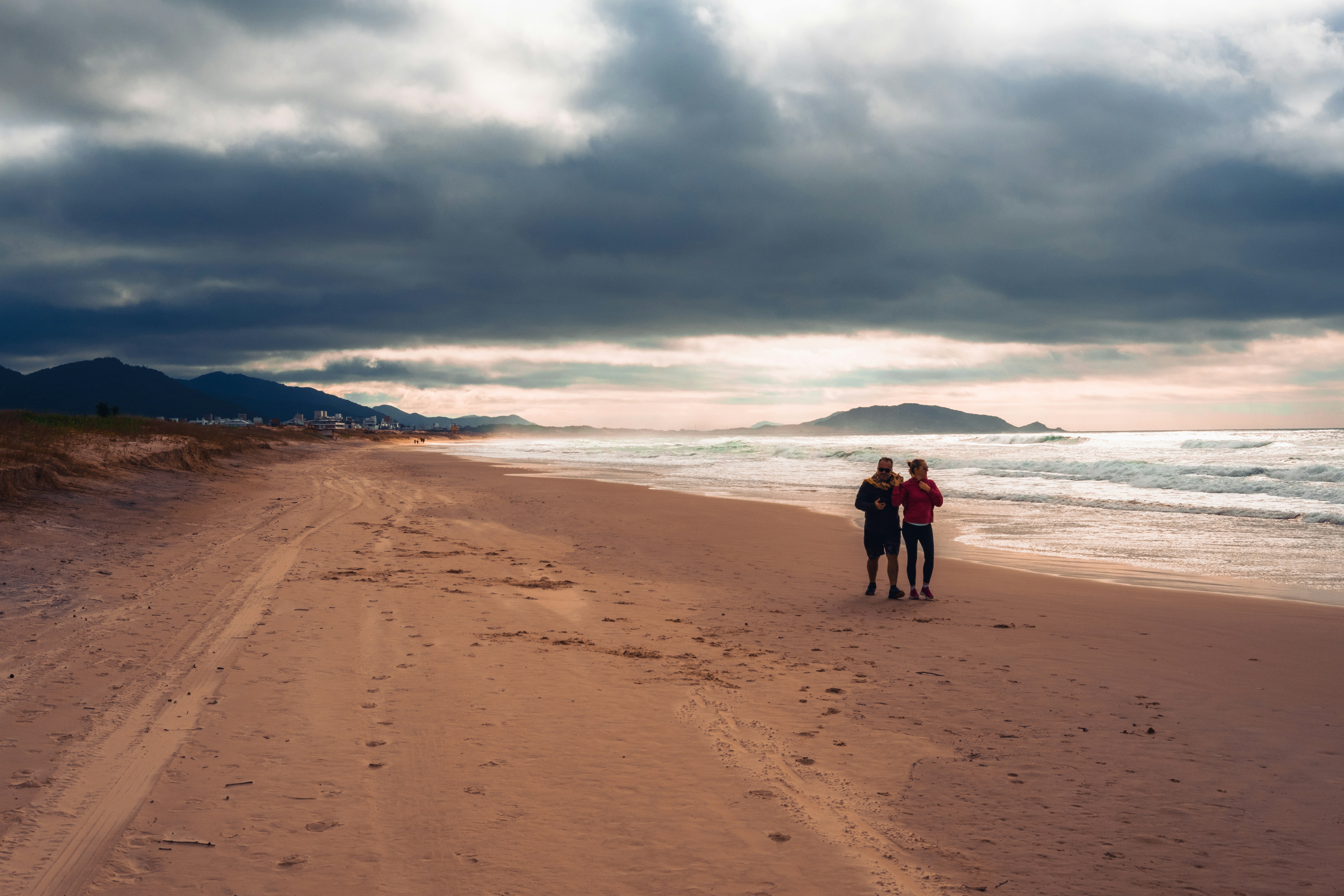 Two Silhouetted Walkers on a Quiet Dune Shore at Sunset