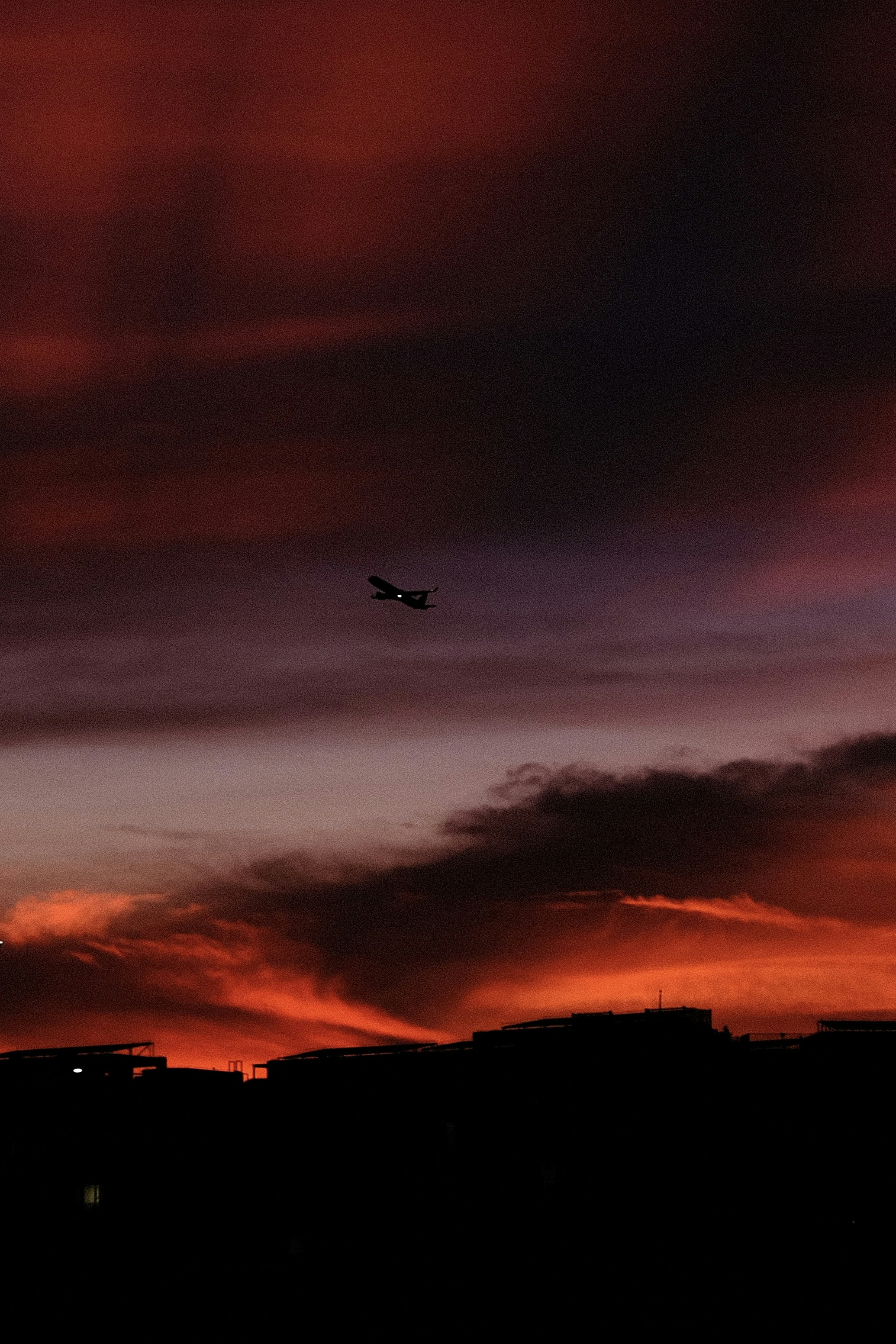 Crimson Hour: A lone jet traces a fiery horizon above a sleeping city