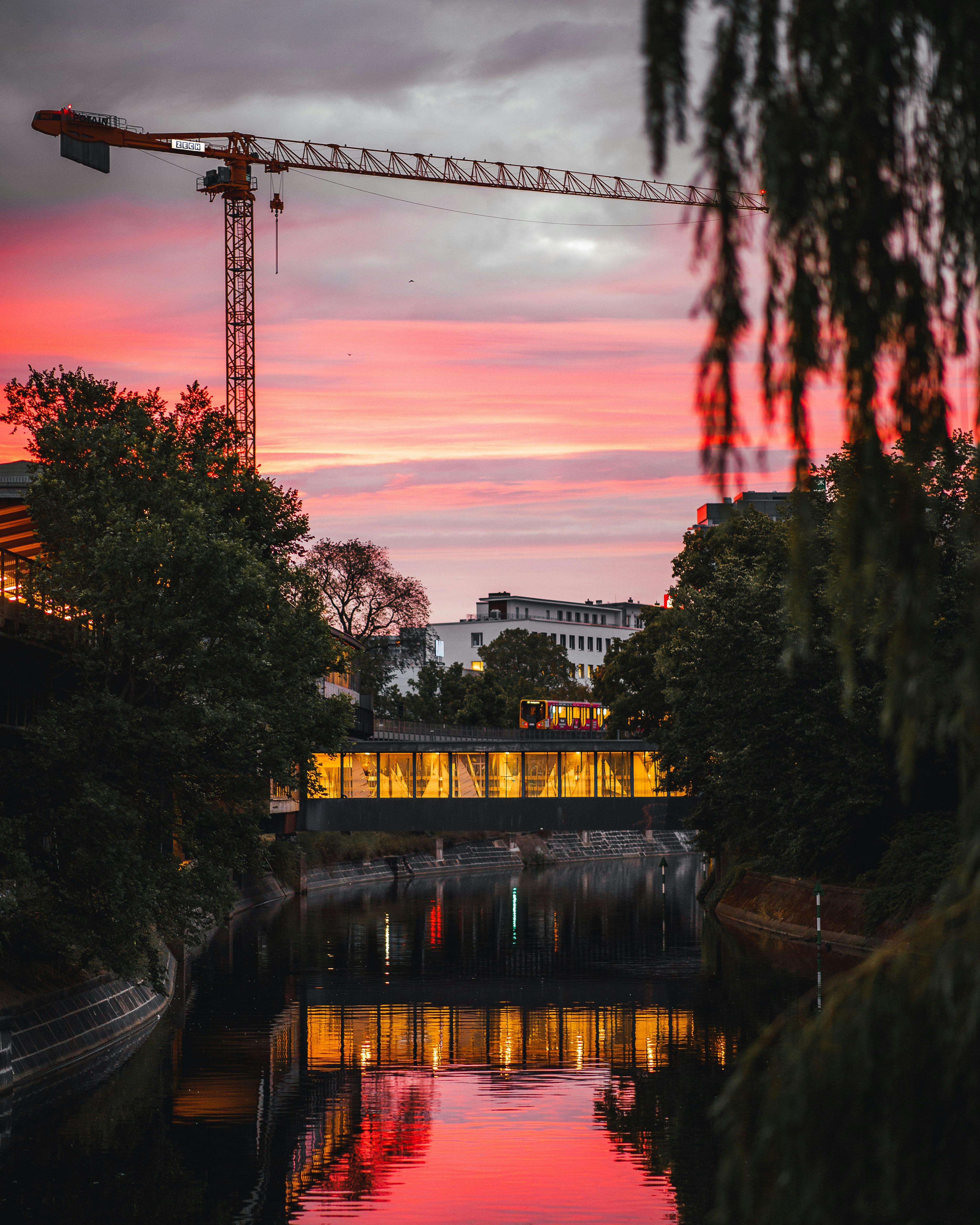 Crane at Dusk: Sunset Threads Gold Across an Urban Canal