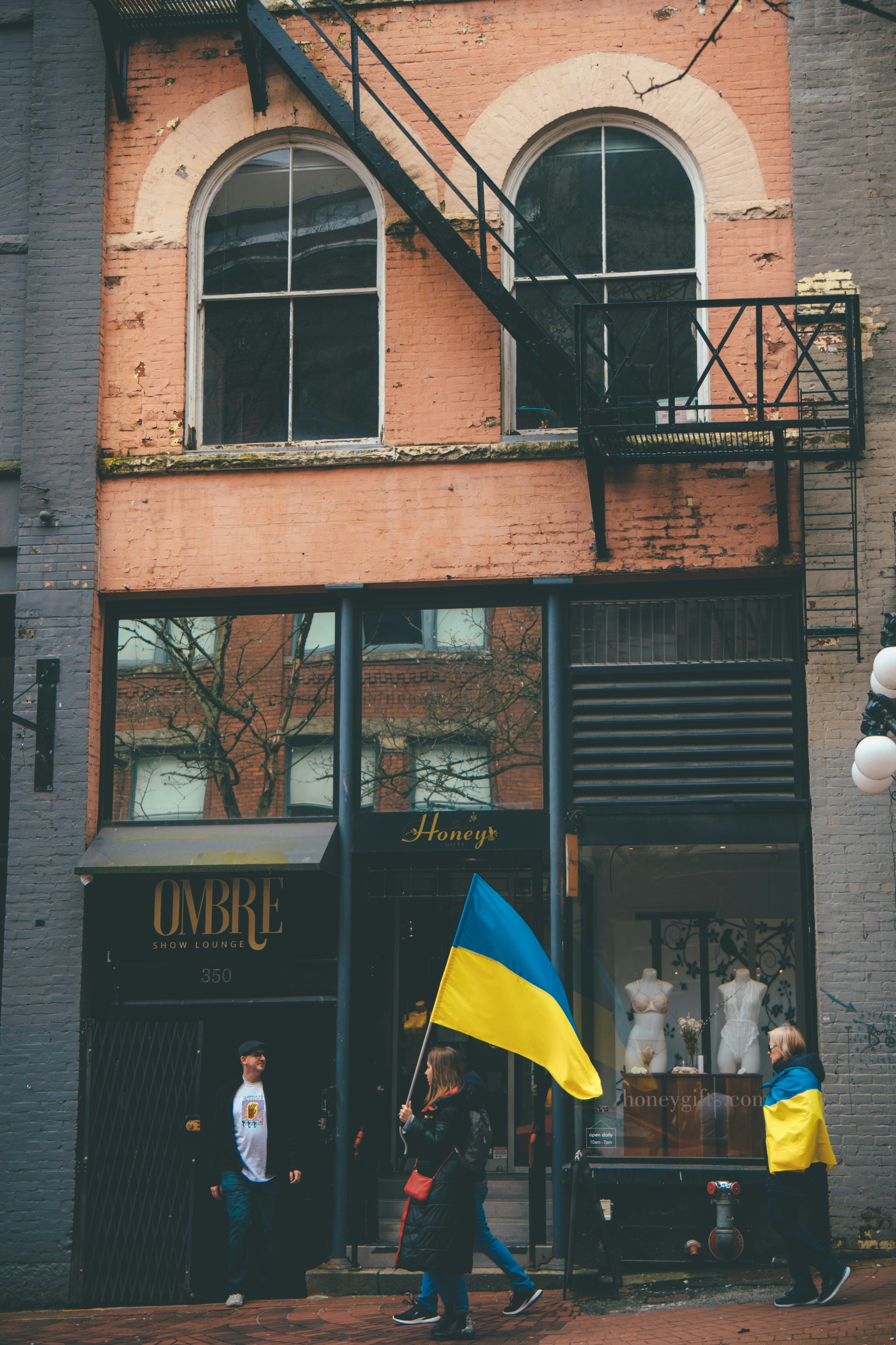 a group of people walking by a building with a flag