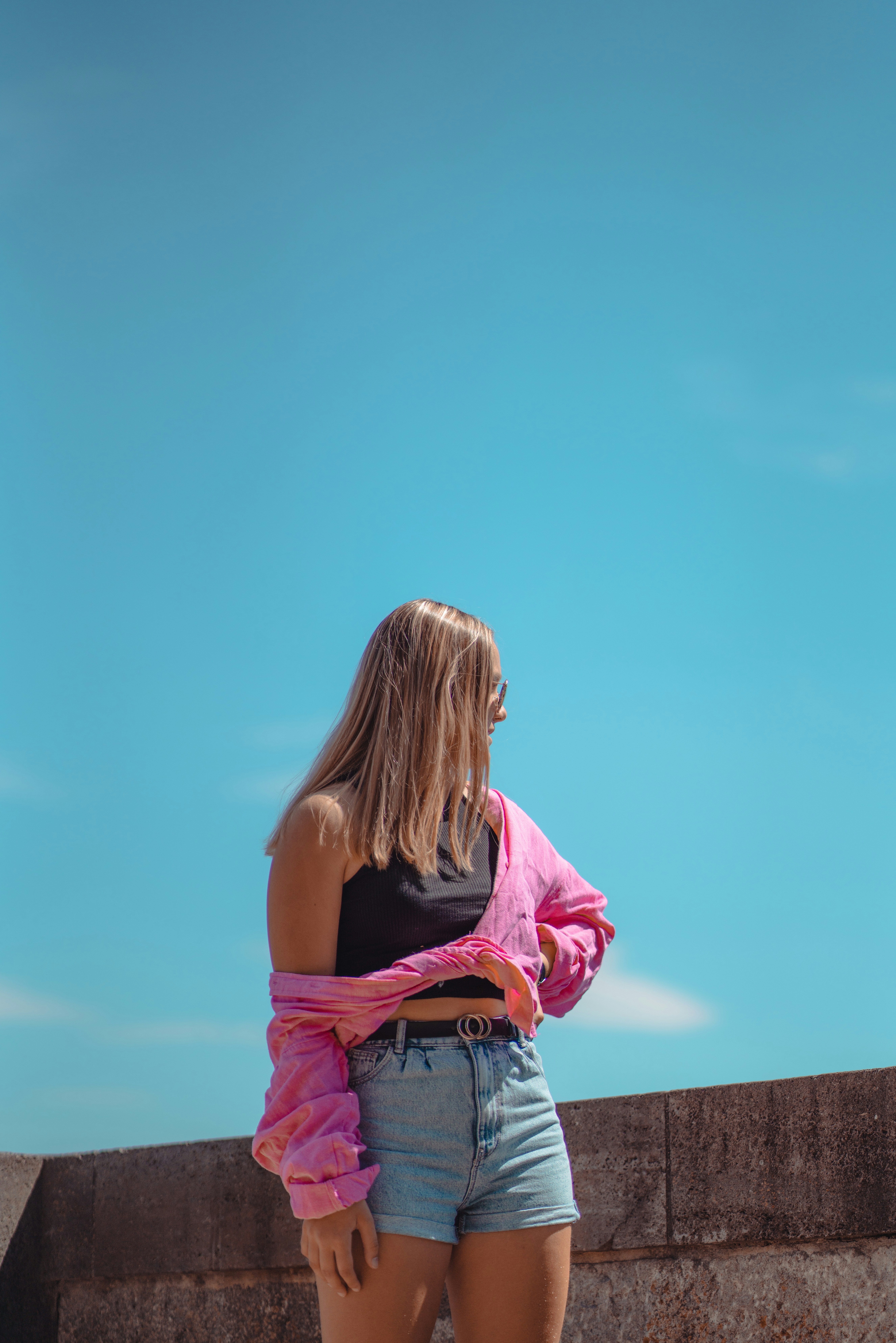 Azure Sky Portrait: Casual Confidence by the Concrete Barrier