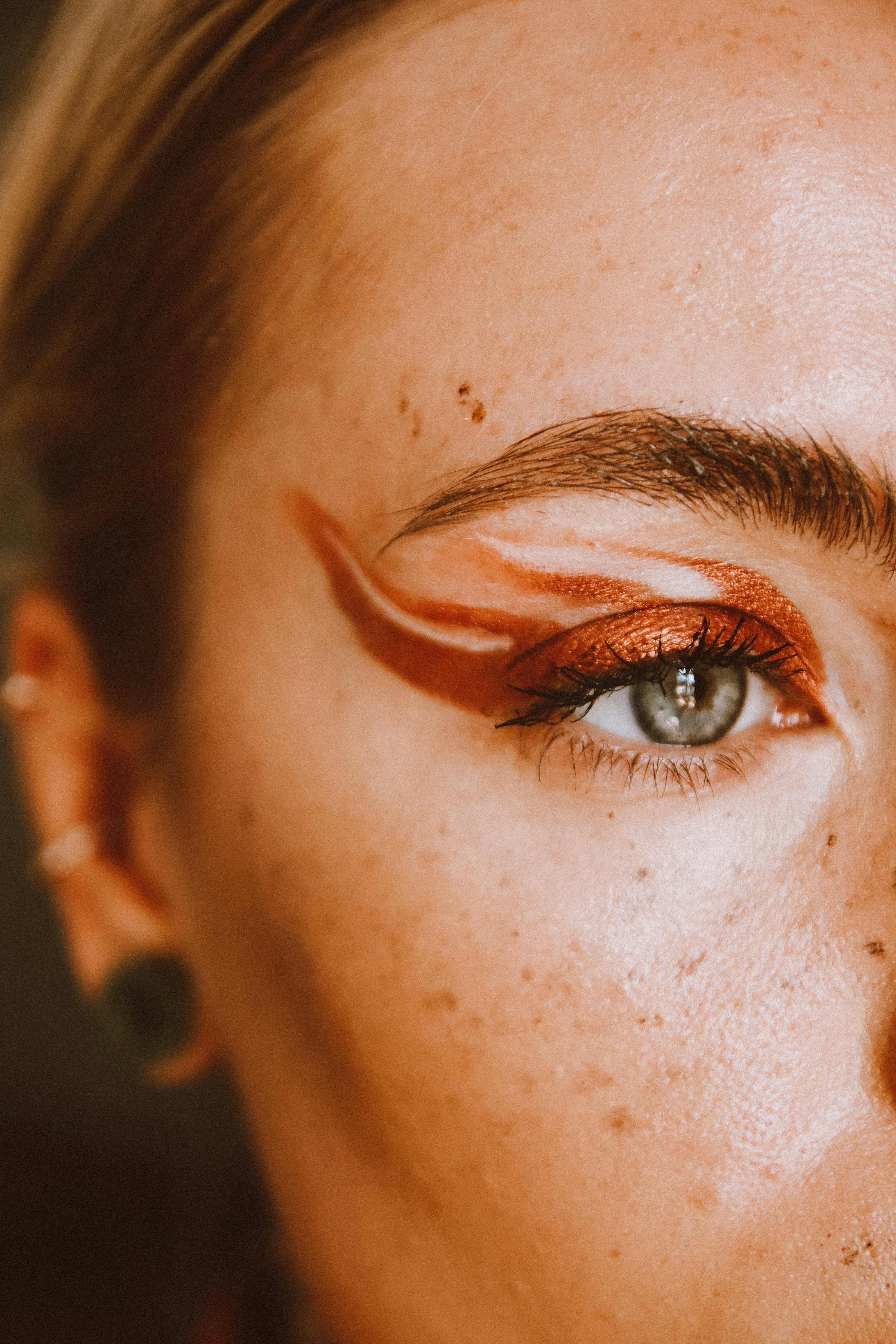 Cat-Eye Ember: Close-Up Portrait with Bold Red Wing and Warm Glow