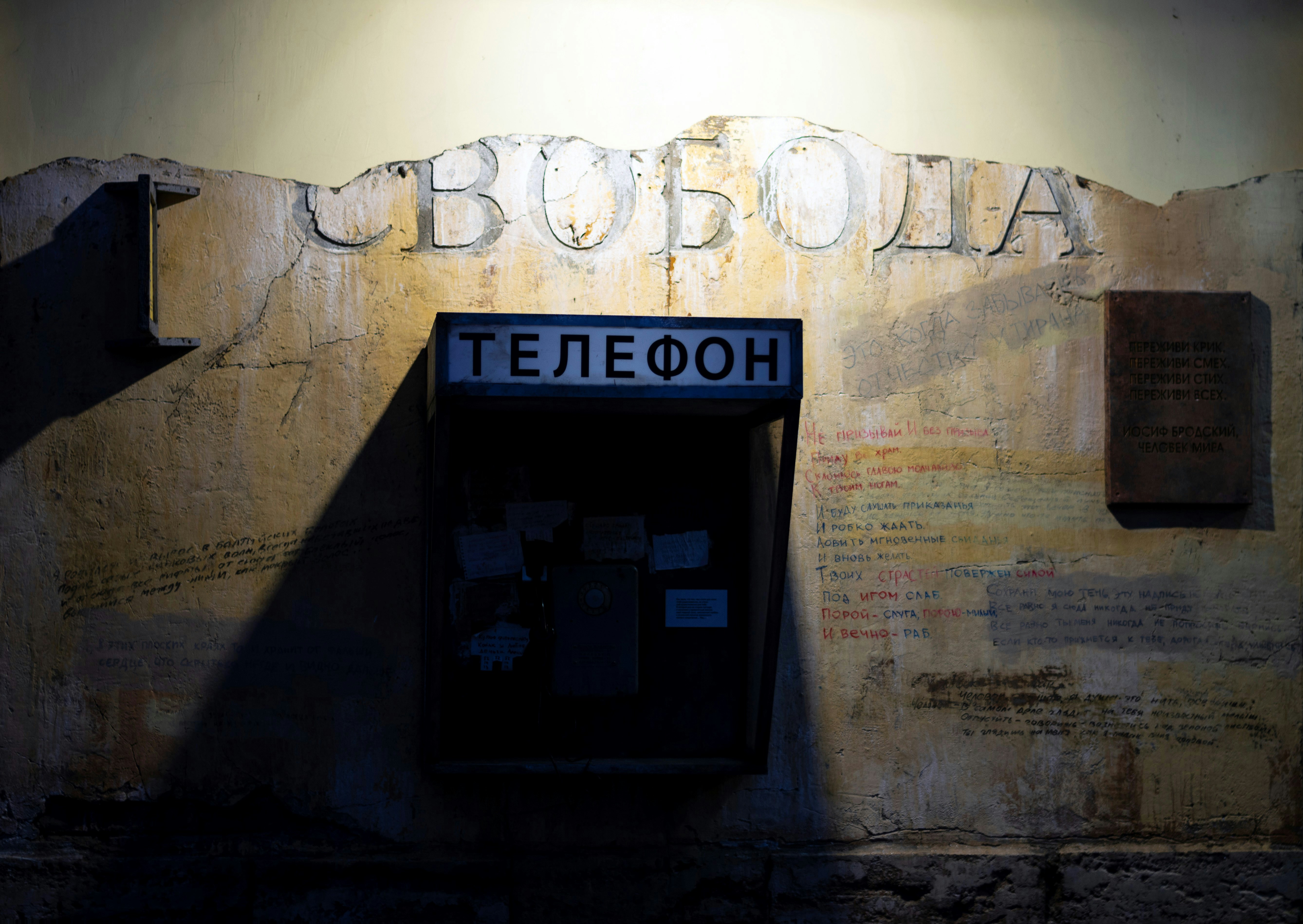 Phone Booth Under a Weathered Sign in Dim Light