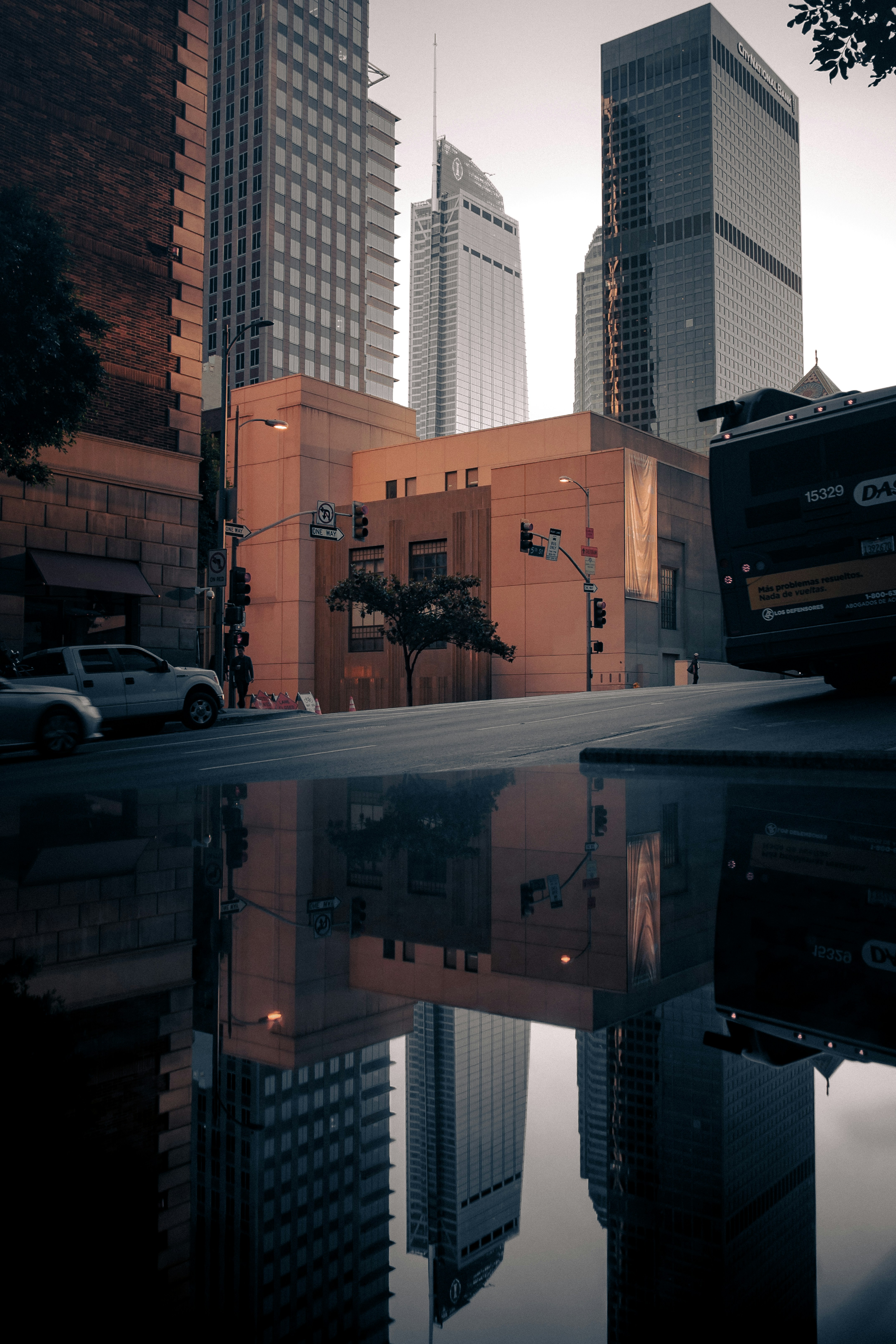 City skyline reflecting in a puddle on the street, showcasing modern architecture and urban life.