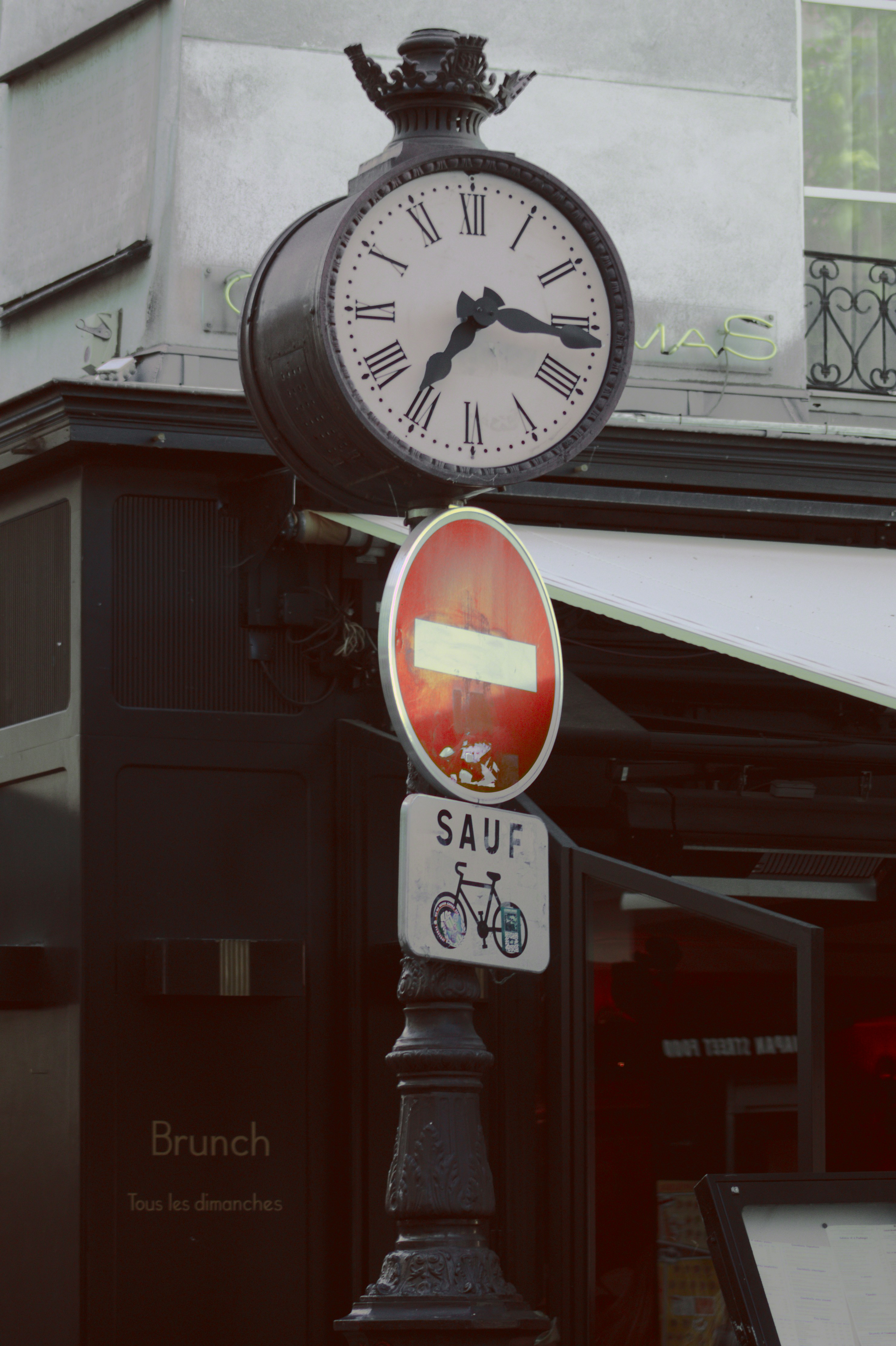 A clock in Paris with signs for bikes. 