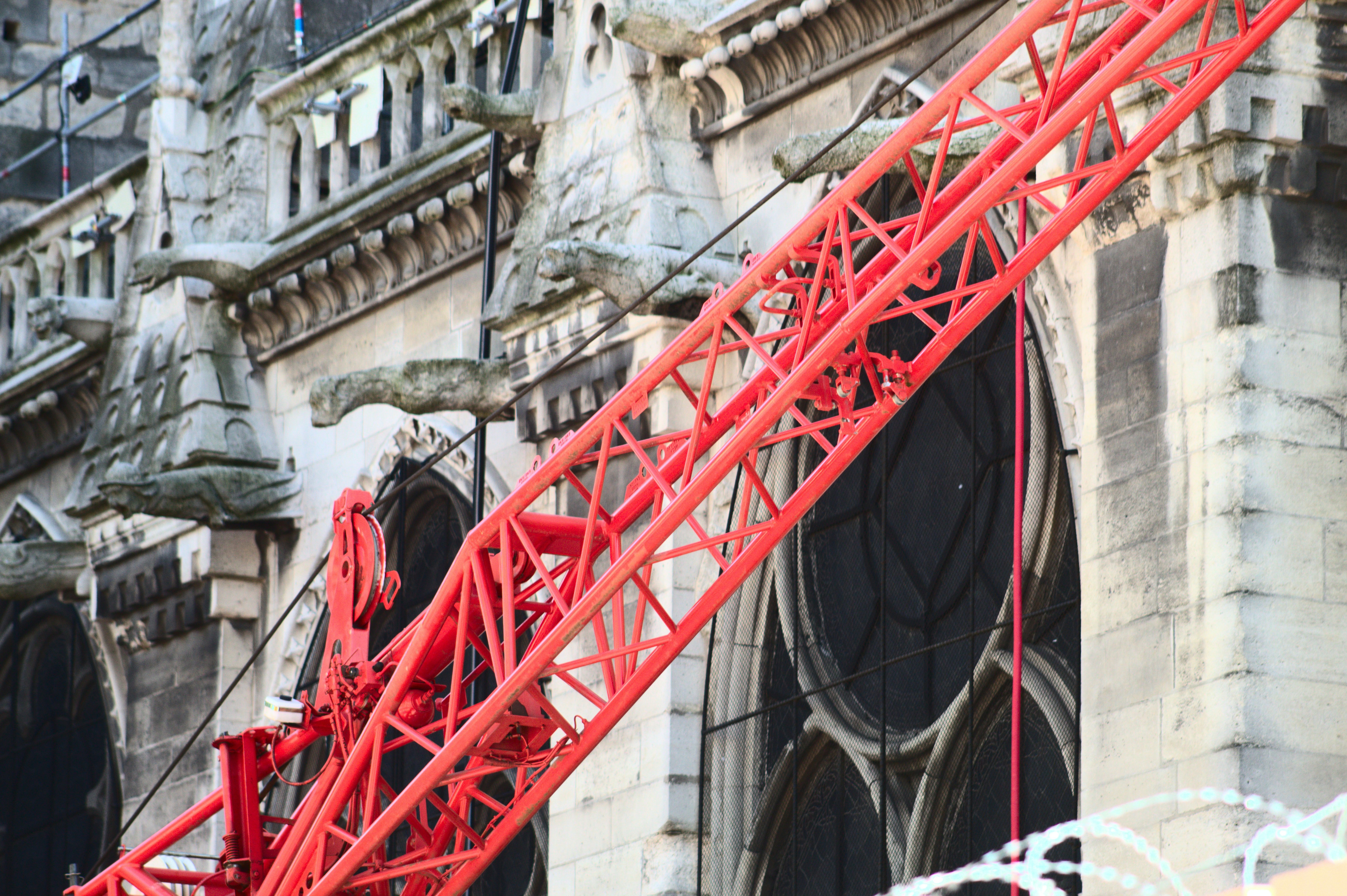 Crimson Crane Slicing Through Time: Red Lattice Against a Stone Facade