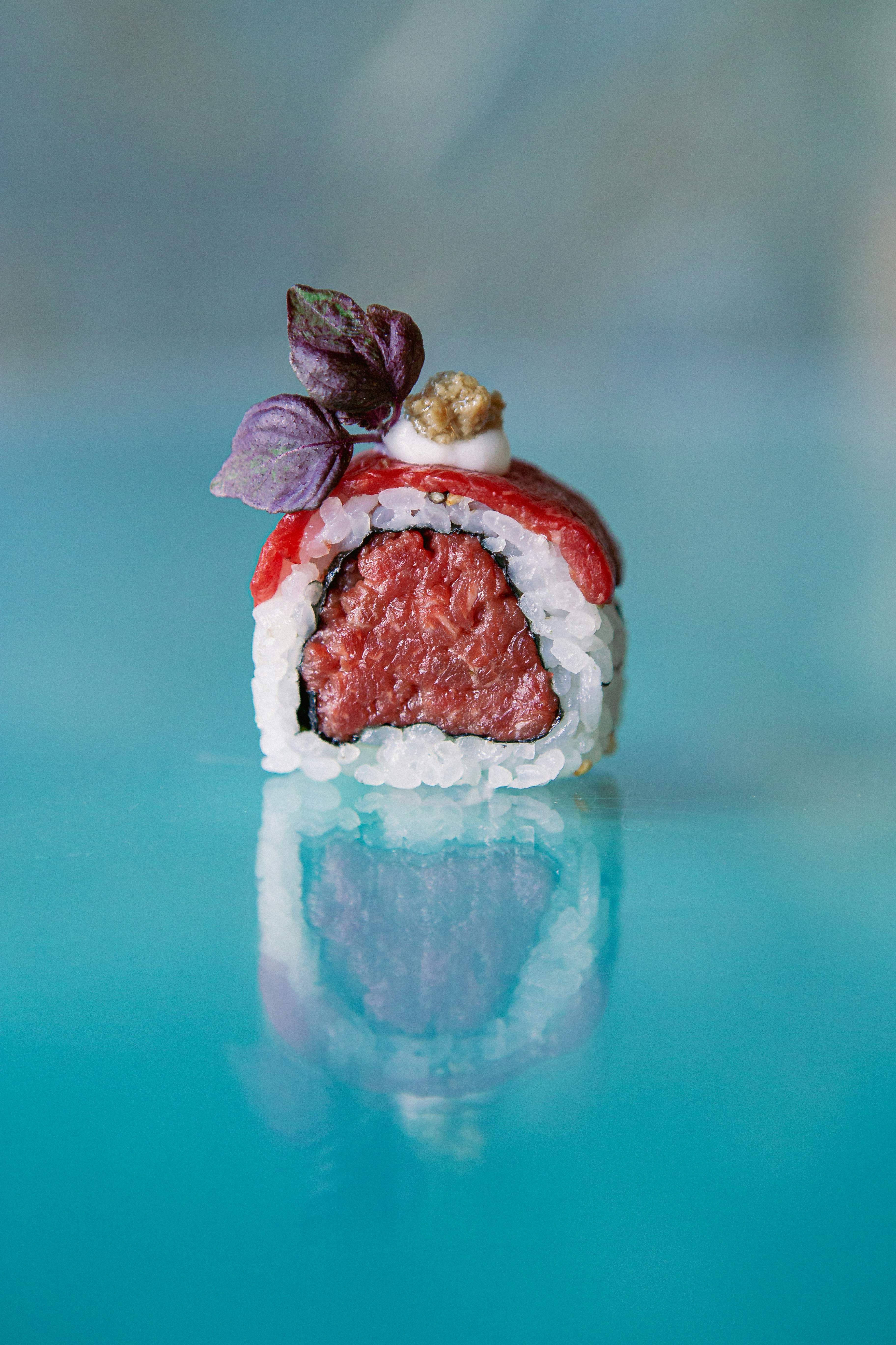 Single Sushi Roll in Focus: Red Center on Blue Reflections
