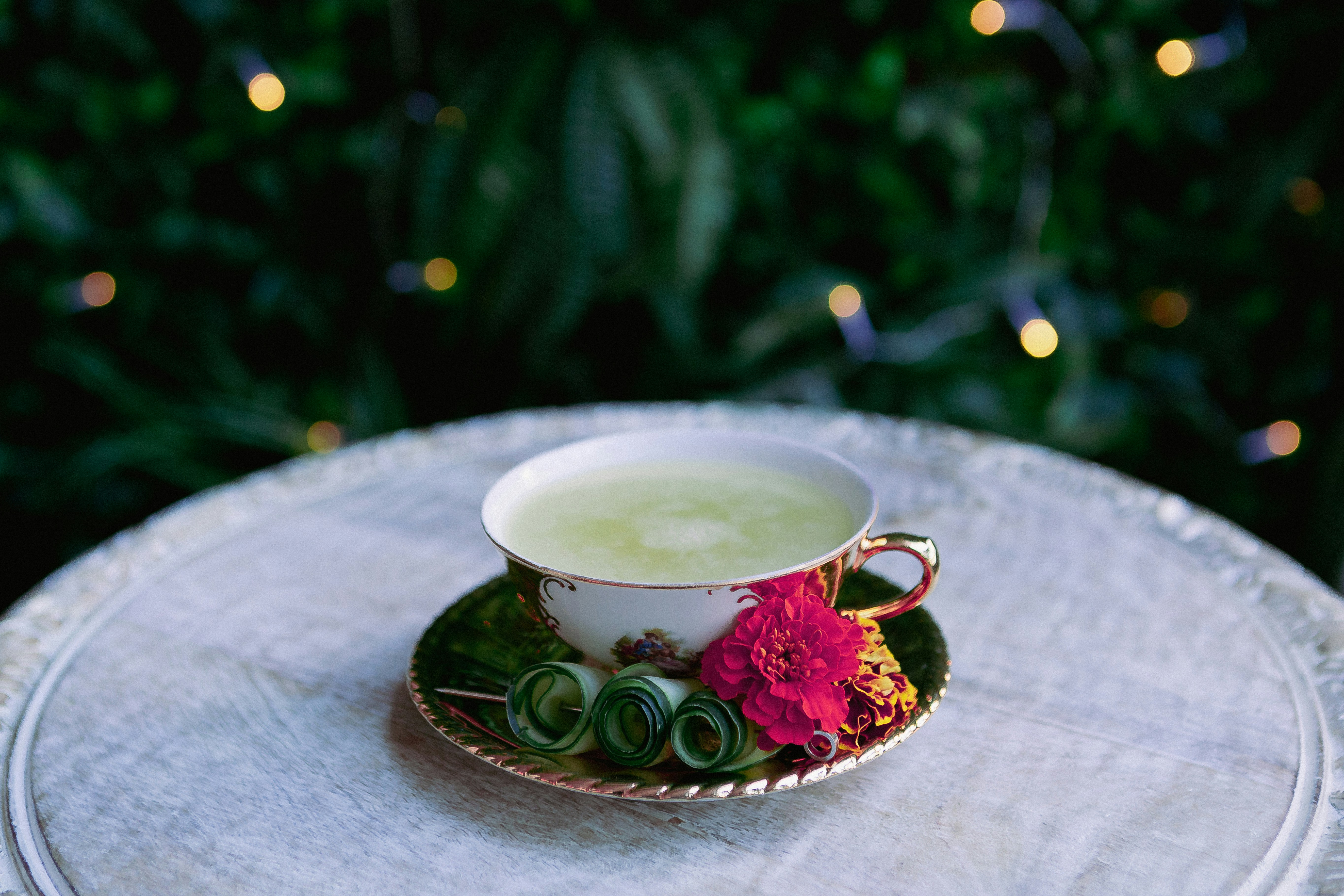 Porcelain Tea Beneath Fairy Lights on a Weathered Round Table