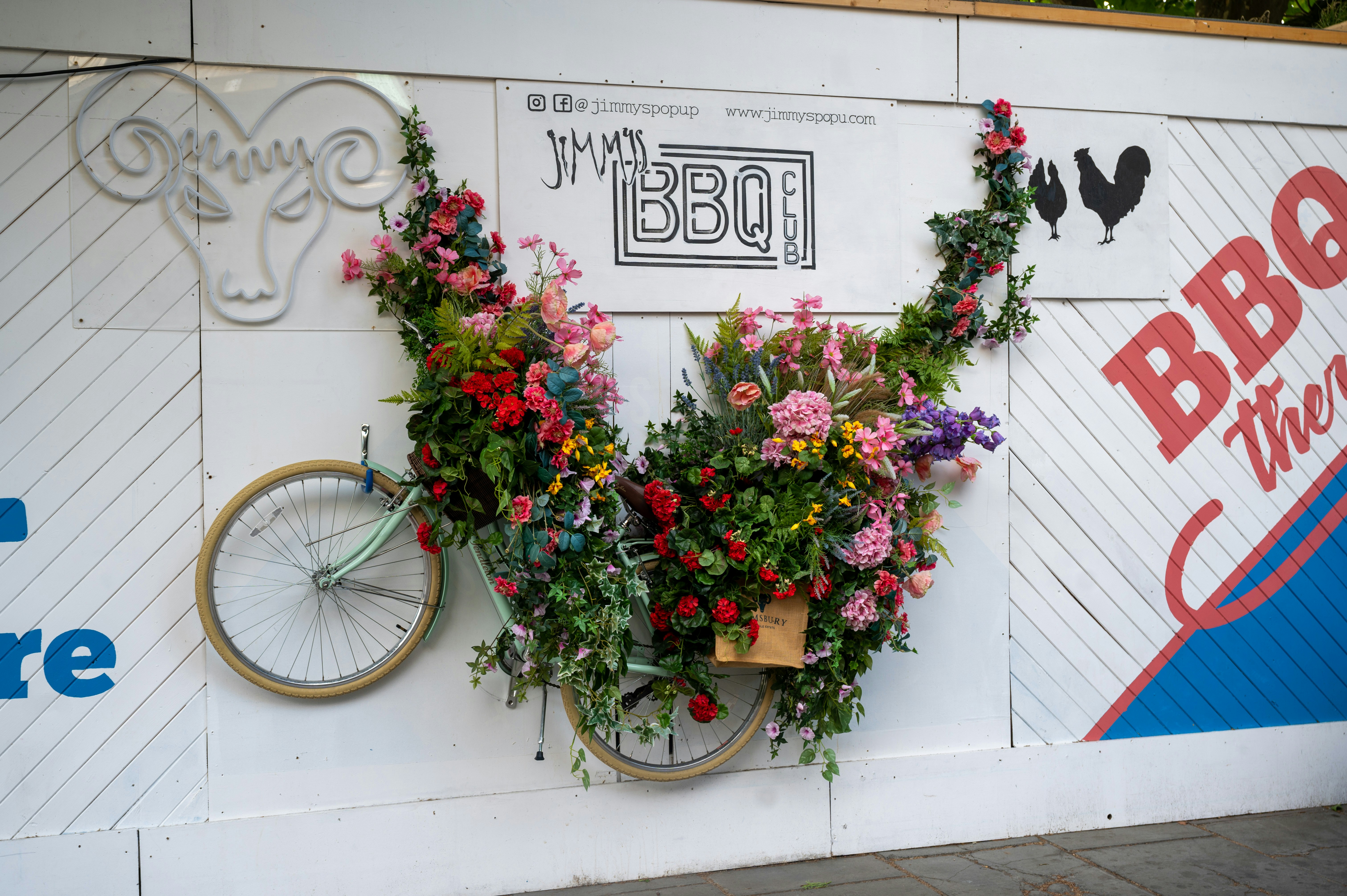 Floral Wheelbarrow Bloom: A Bicycle Garden on the Billboard Wall