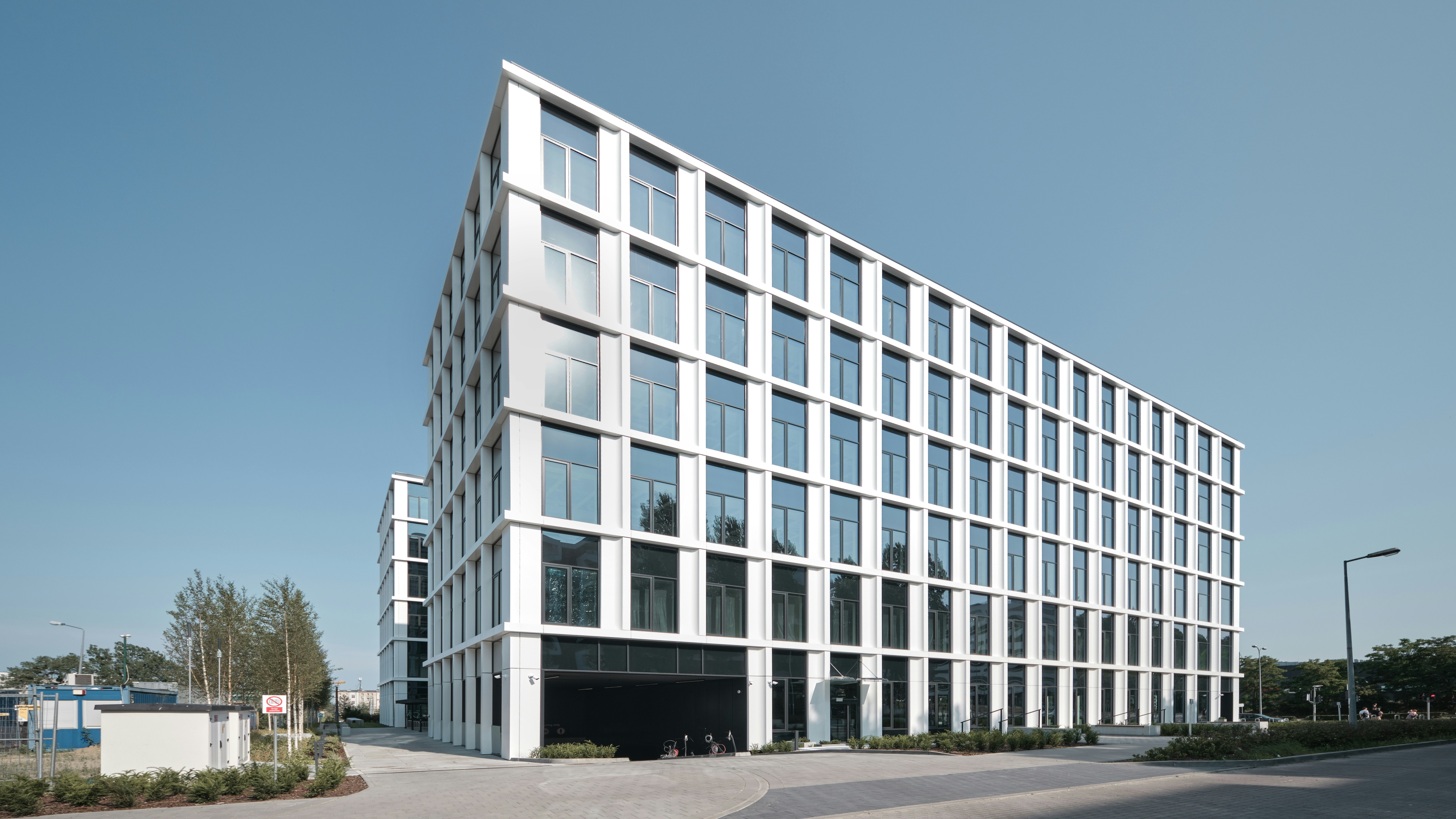 Contemporary office building with a grid-like facade under a clear blue sky.
