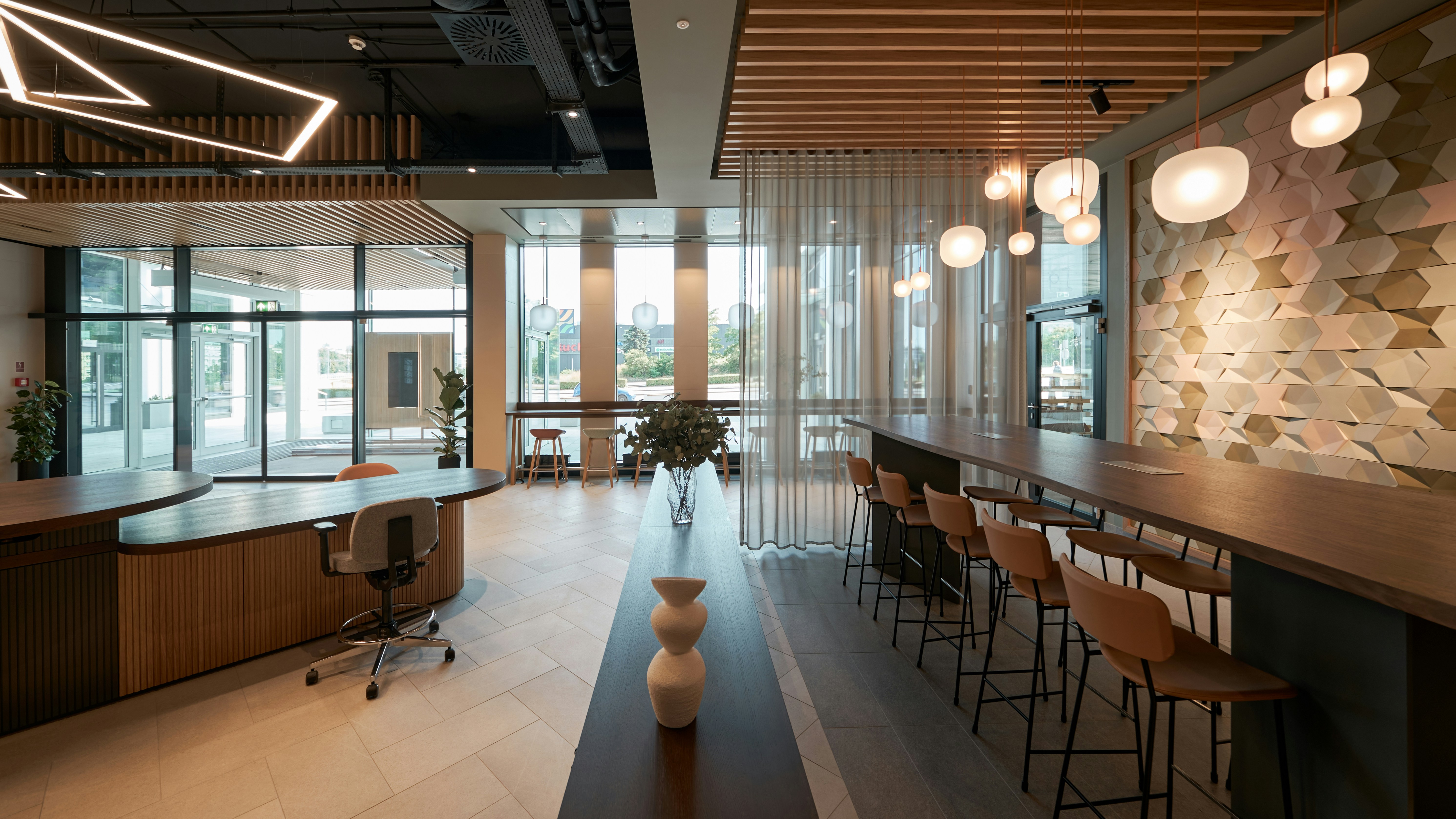 Spacious contemporary office lounge with wooden accents and hanging lights.