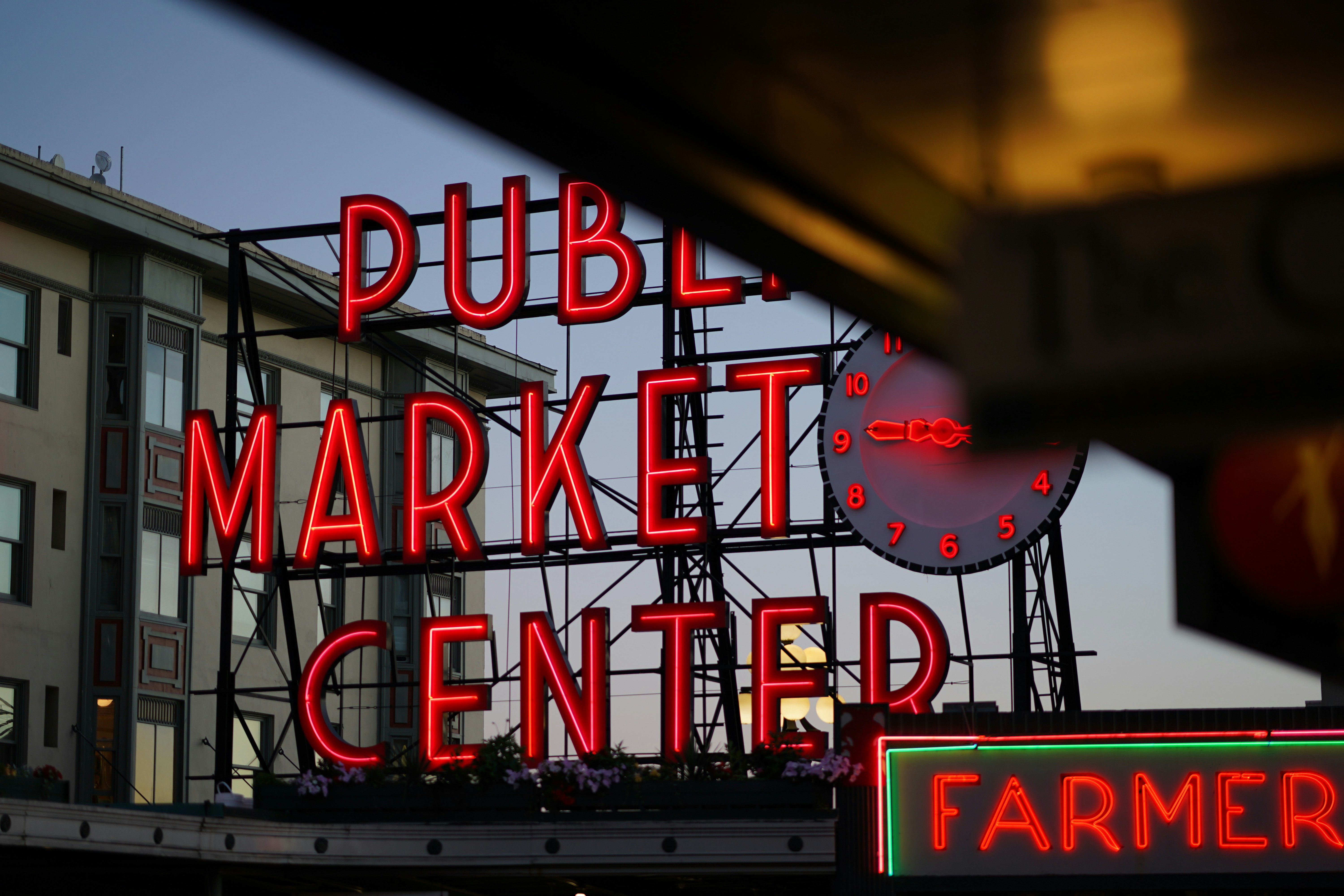Neon Signage Over Downtown: A Market Clock and City Facade