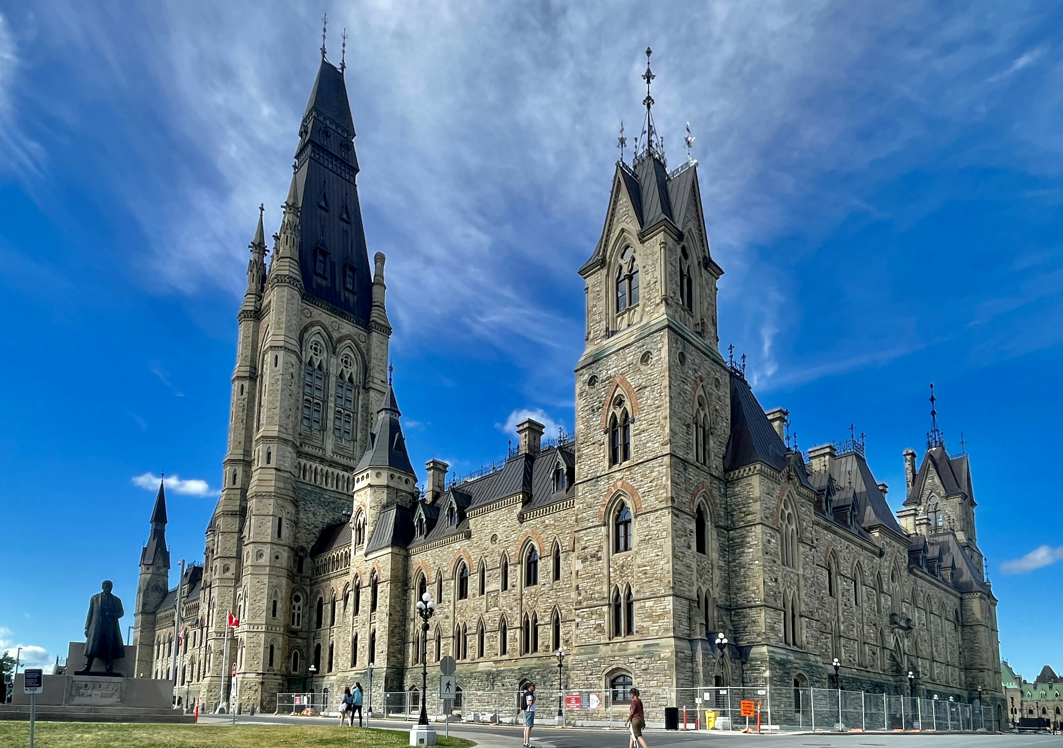 Historic Gothic-style architecture of the Canadian Parliament buildings, showcasing intricate stonework and towering spires against a vibrant sky.