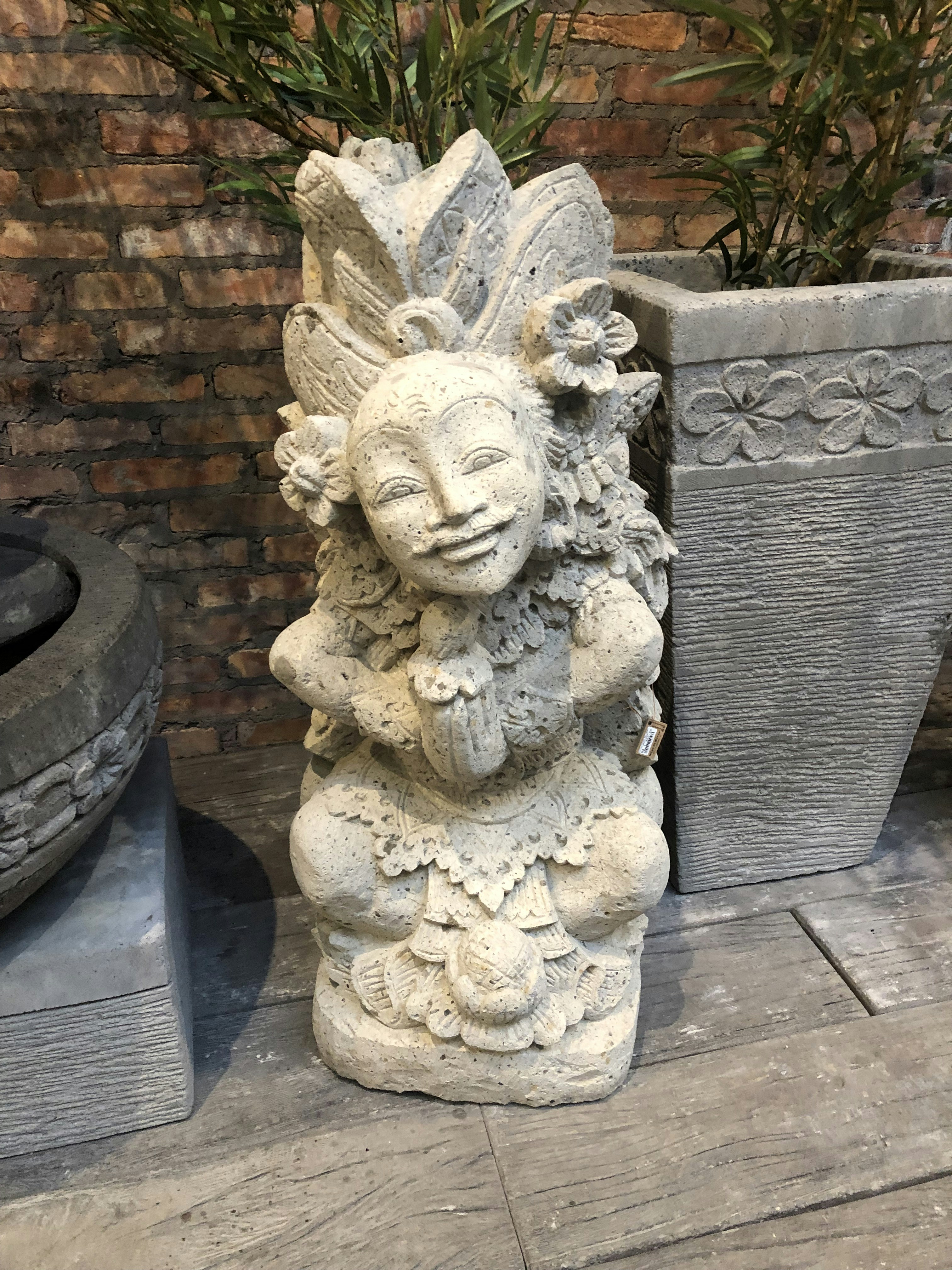 Whimsical Stone Guardian: A Garden Figurine Beside Planters