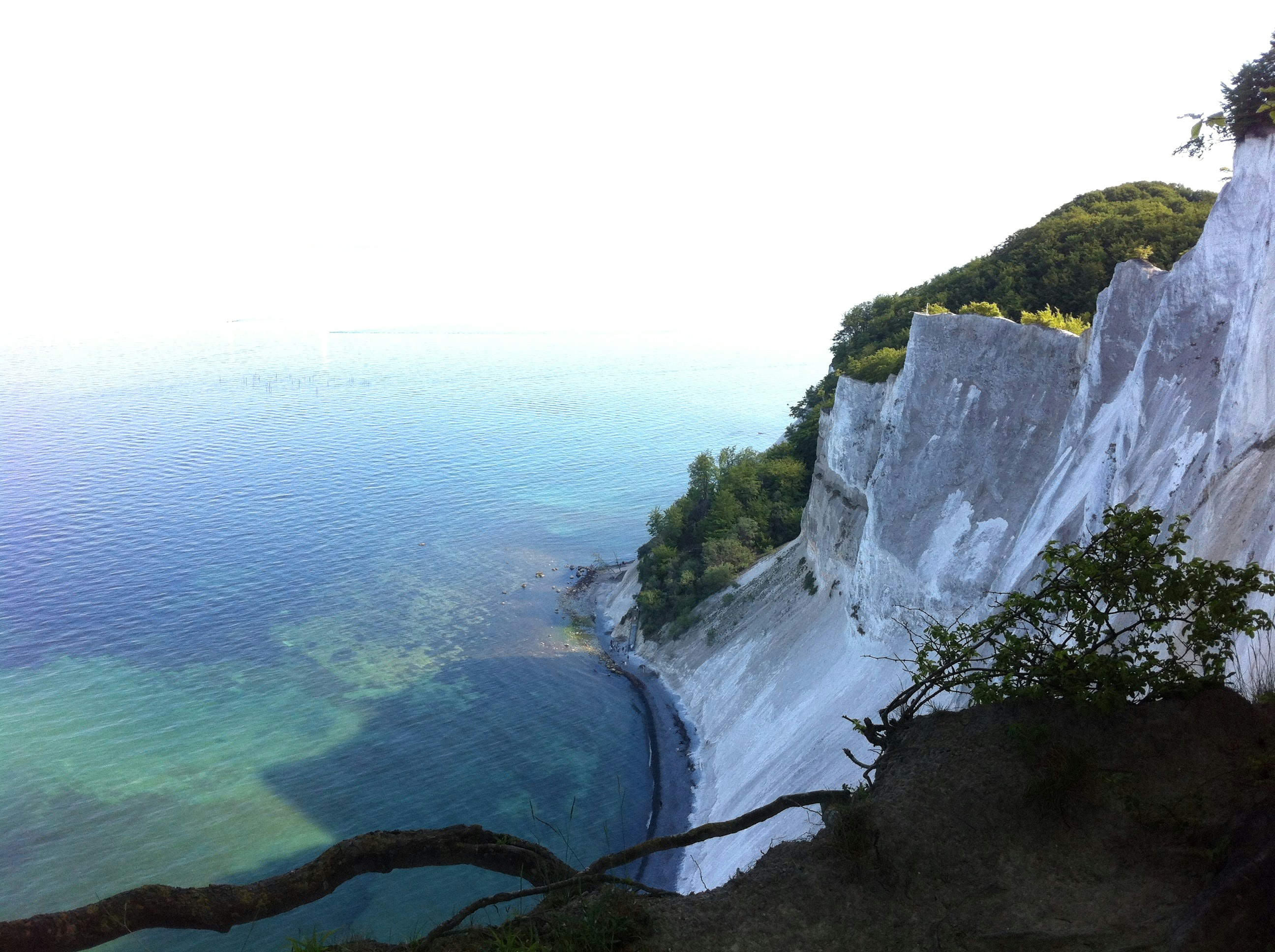 Dramatic white cliffs rise above a tranquil sea, showcasing the interplay of land and water. The scene captures the beauty of natural erosion and coastal landscapes.
