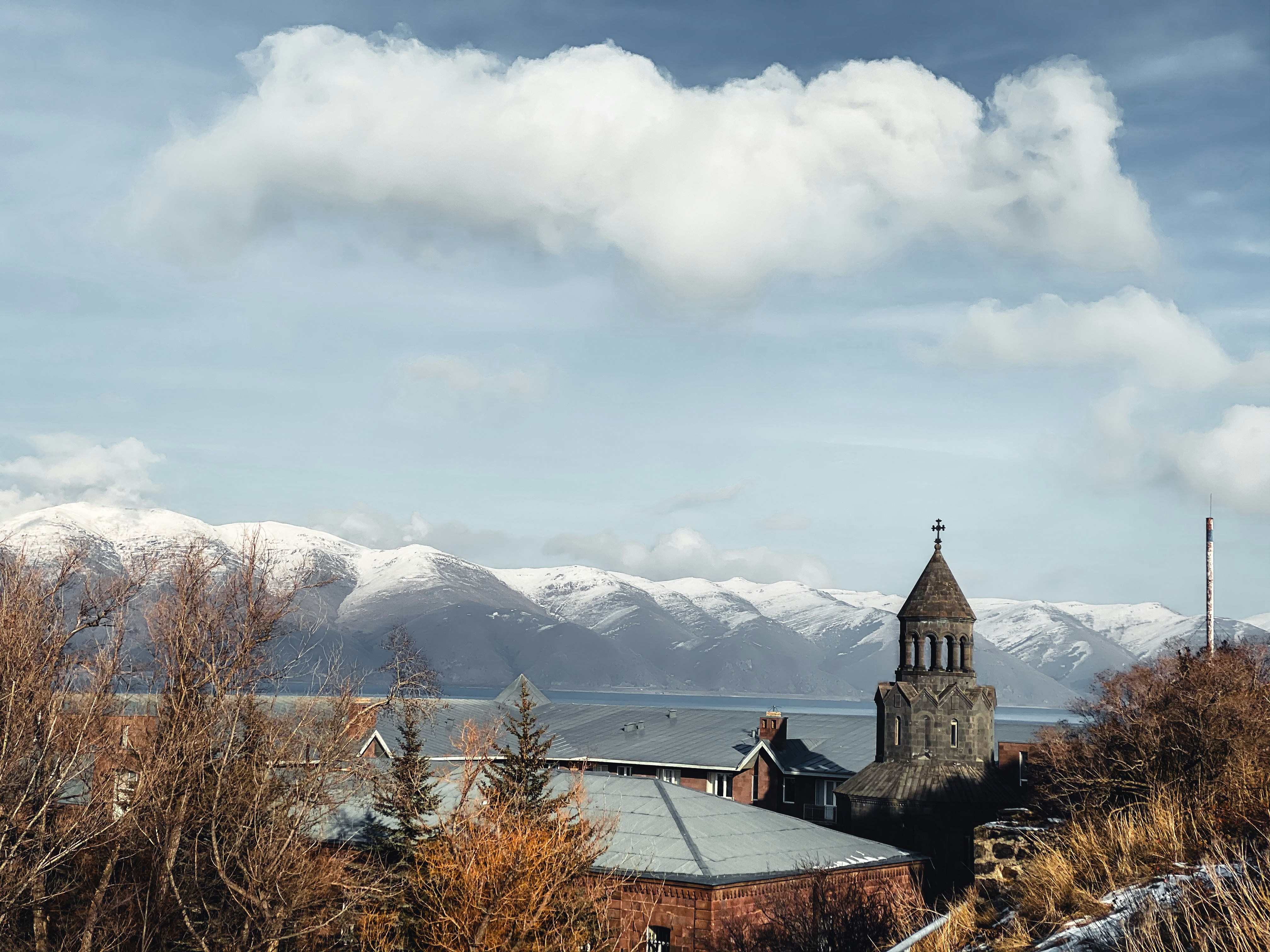 Snow-dusted town with church and distant mountains under a pale sky