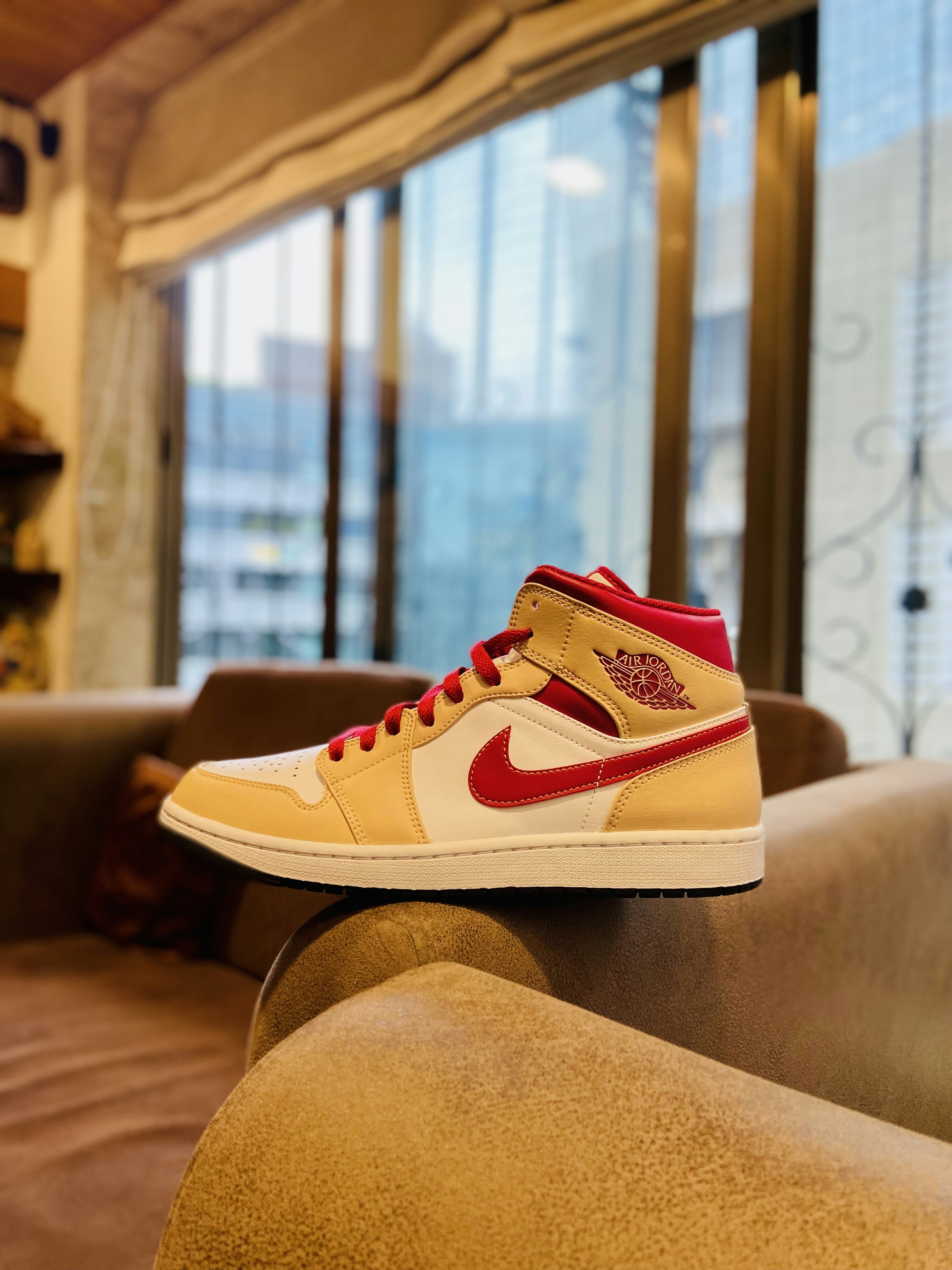 Red-and-cream Nike sneaker perched on a couch arm in a sunlit living room