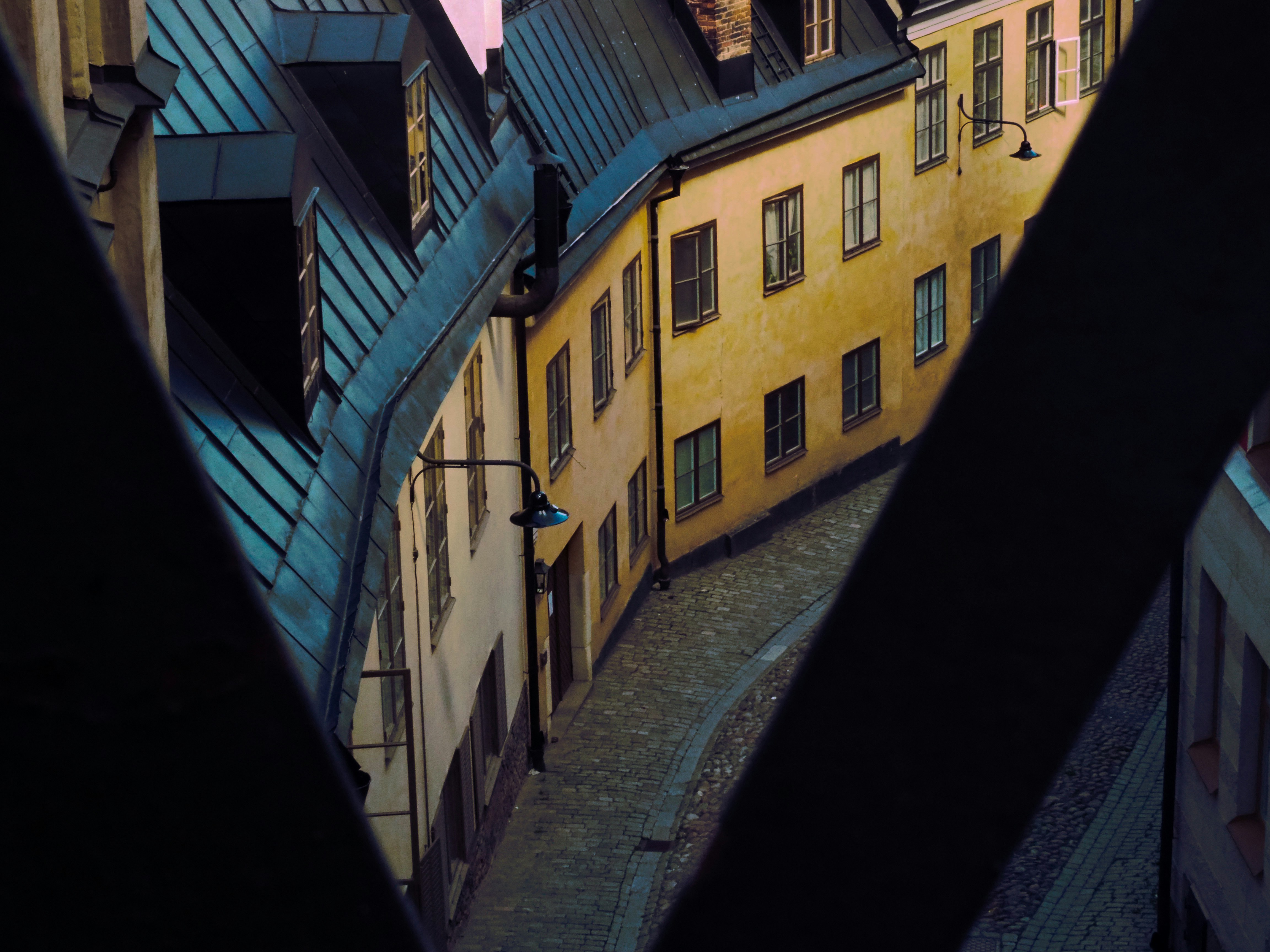 Lamppost on the Curve: A Warm-Cobbled Alley Framed by Steel Shadows