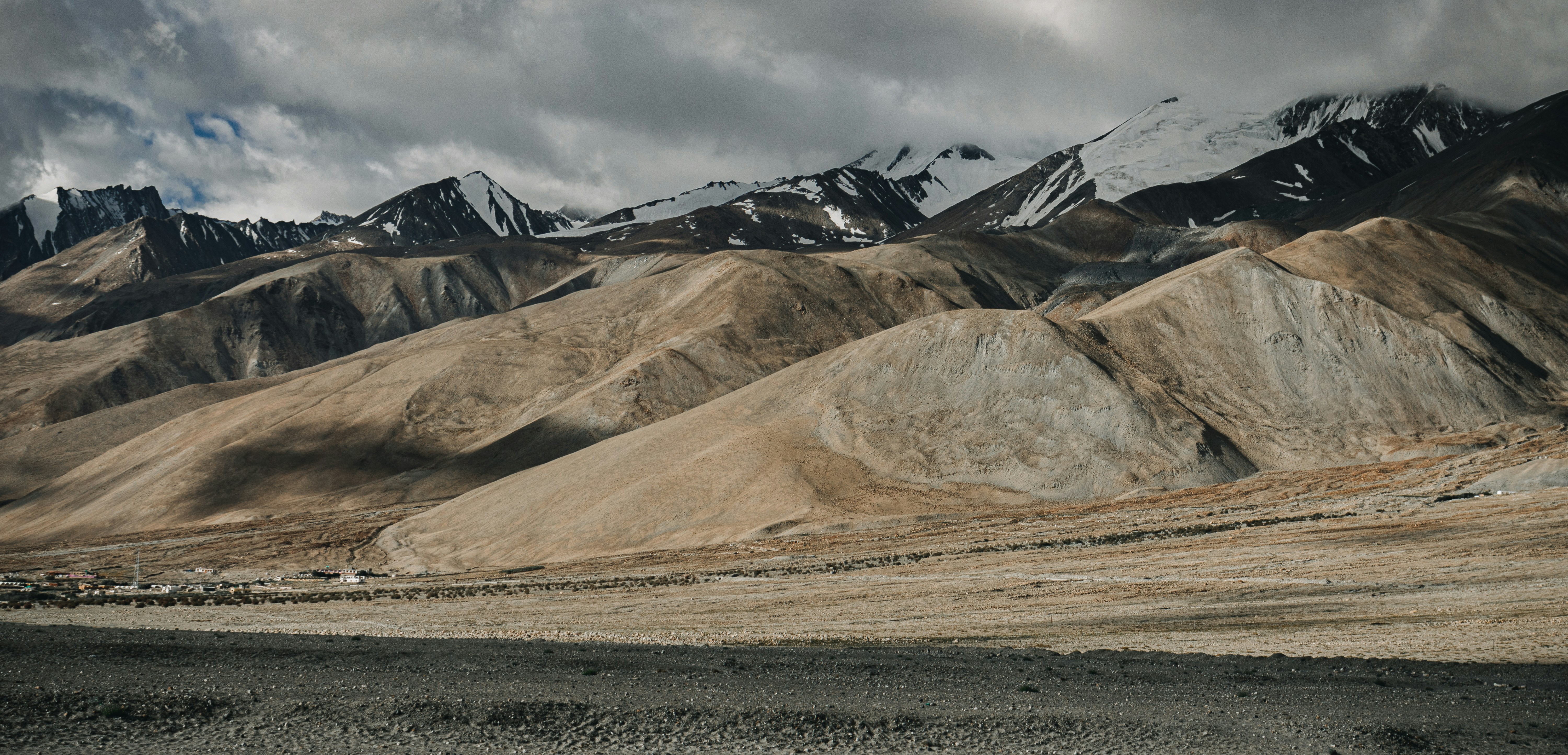 Storm-Worn Peaks Loom Over Desertic Ridges