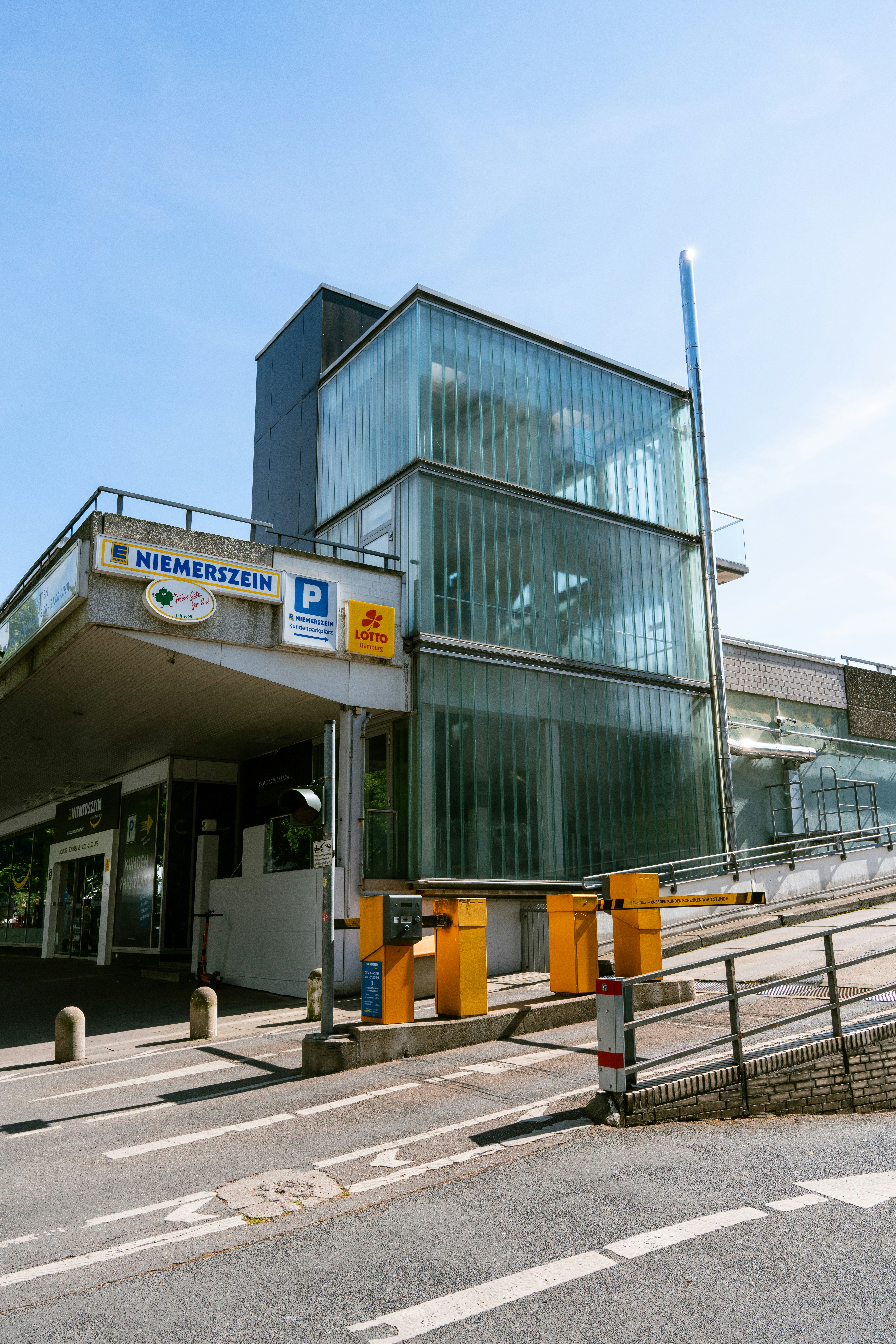 Glass Atrium Rising Over a Parking Gate in Daylight