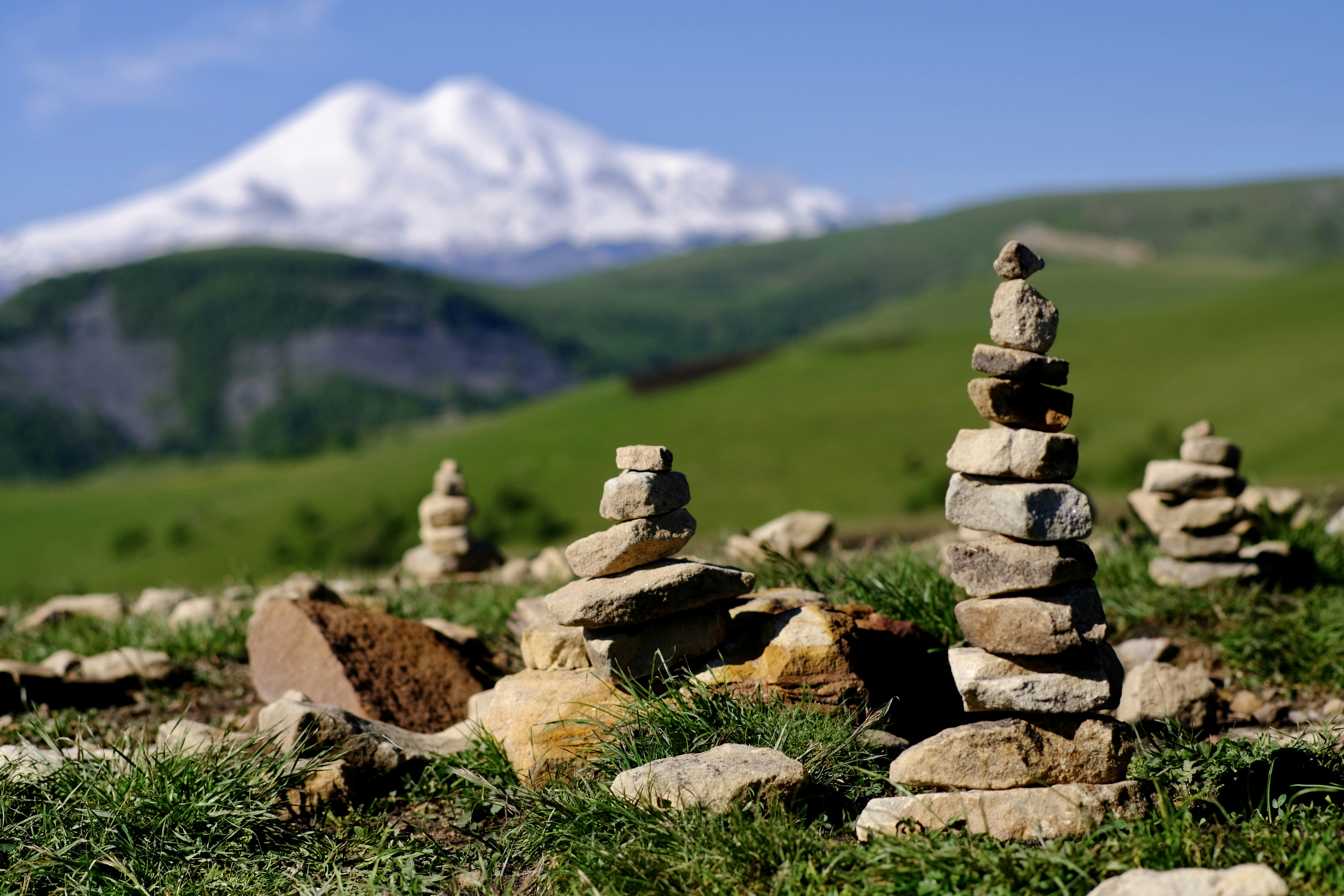 Stacked Stones in a Sunlit Highland with Snow-Capped Peak