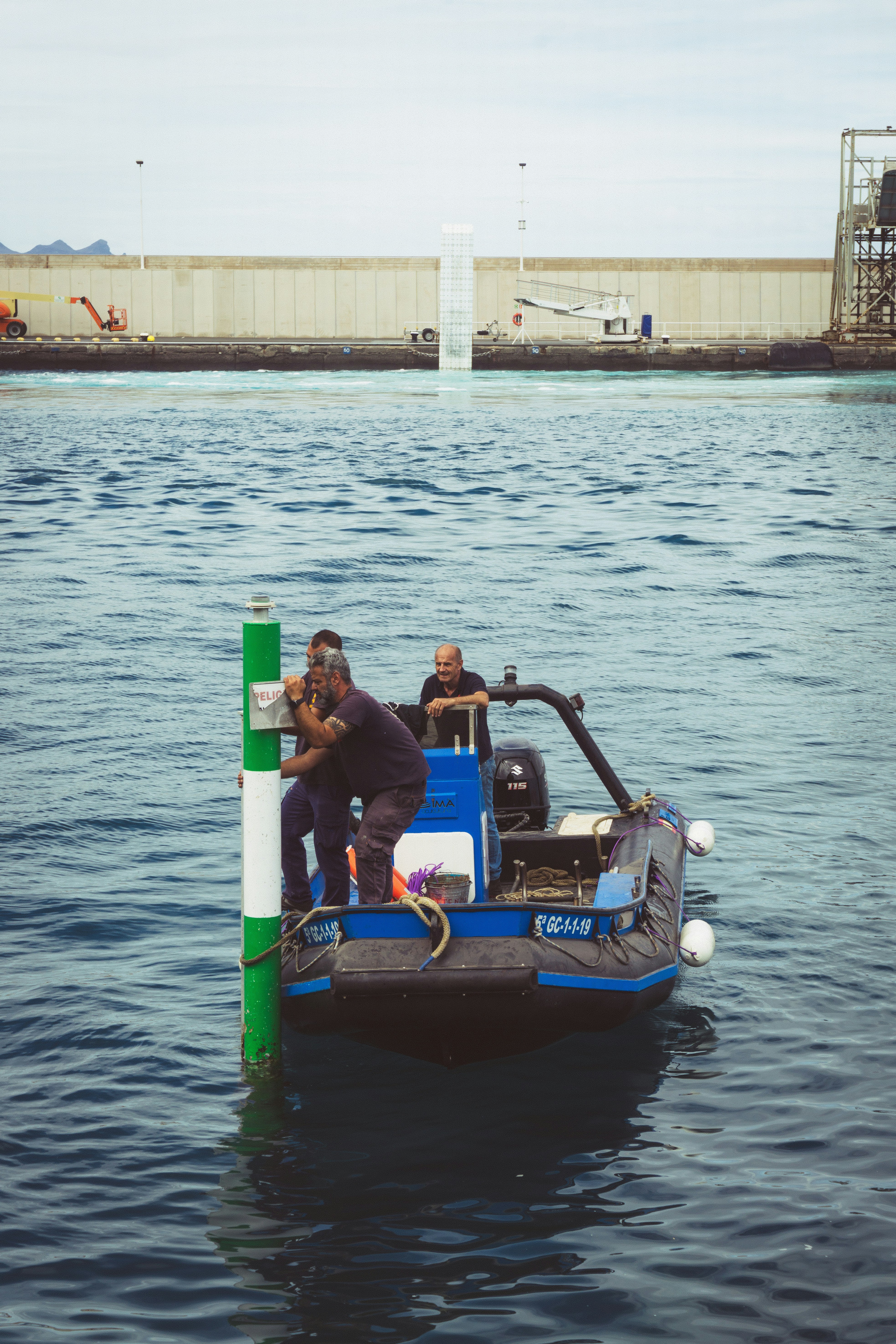 Tow to the Pier: A Small Boat Clings to a Green-and-White Marker