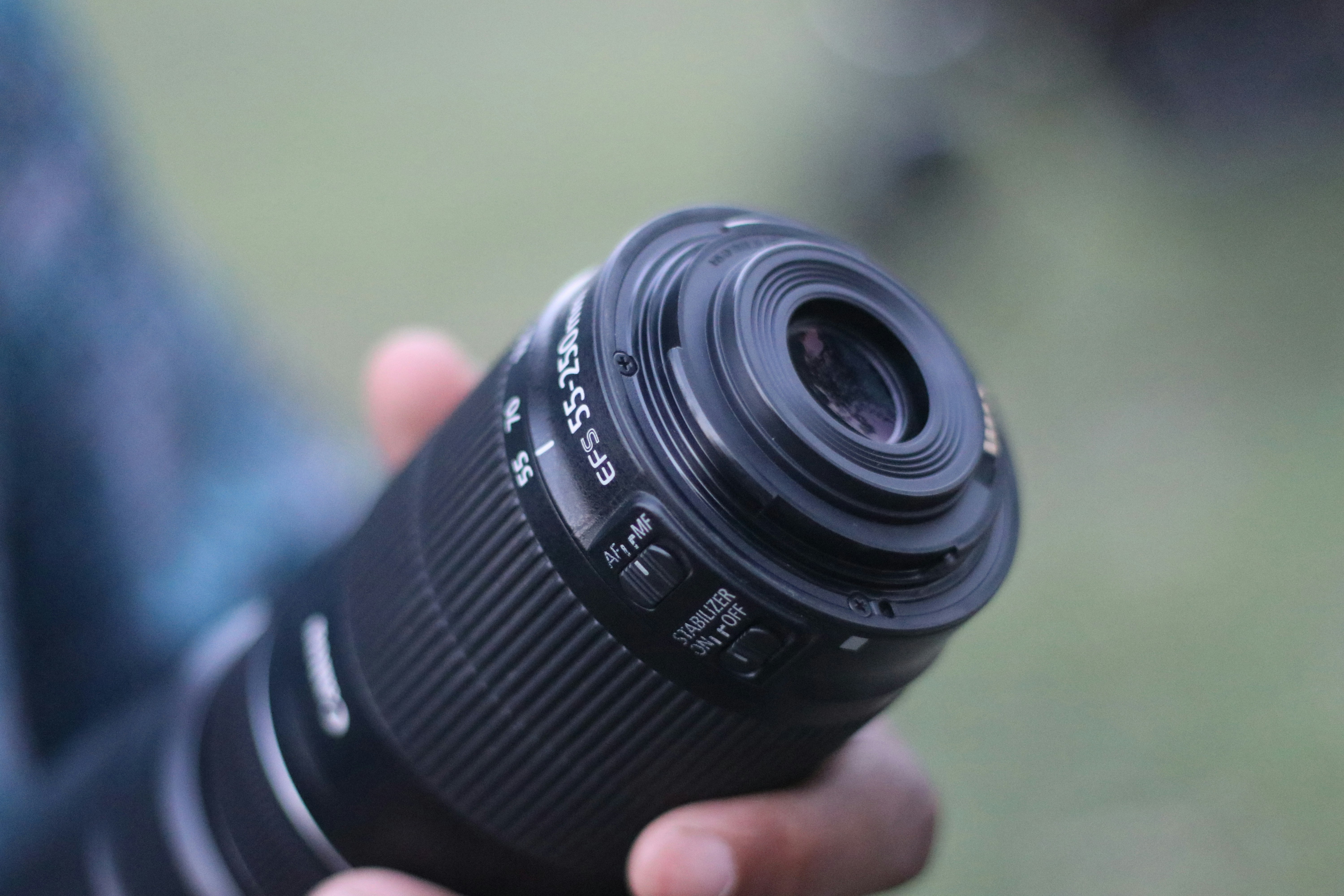Focused Grip: A Canon Lens Captured in Hand with Soft Bokeh