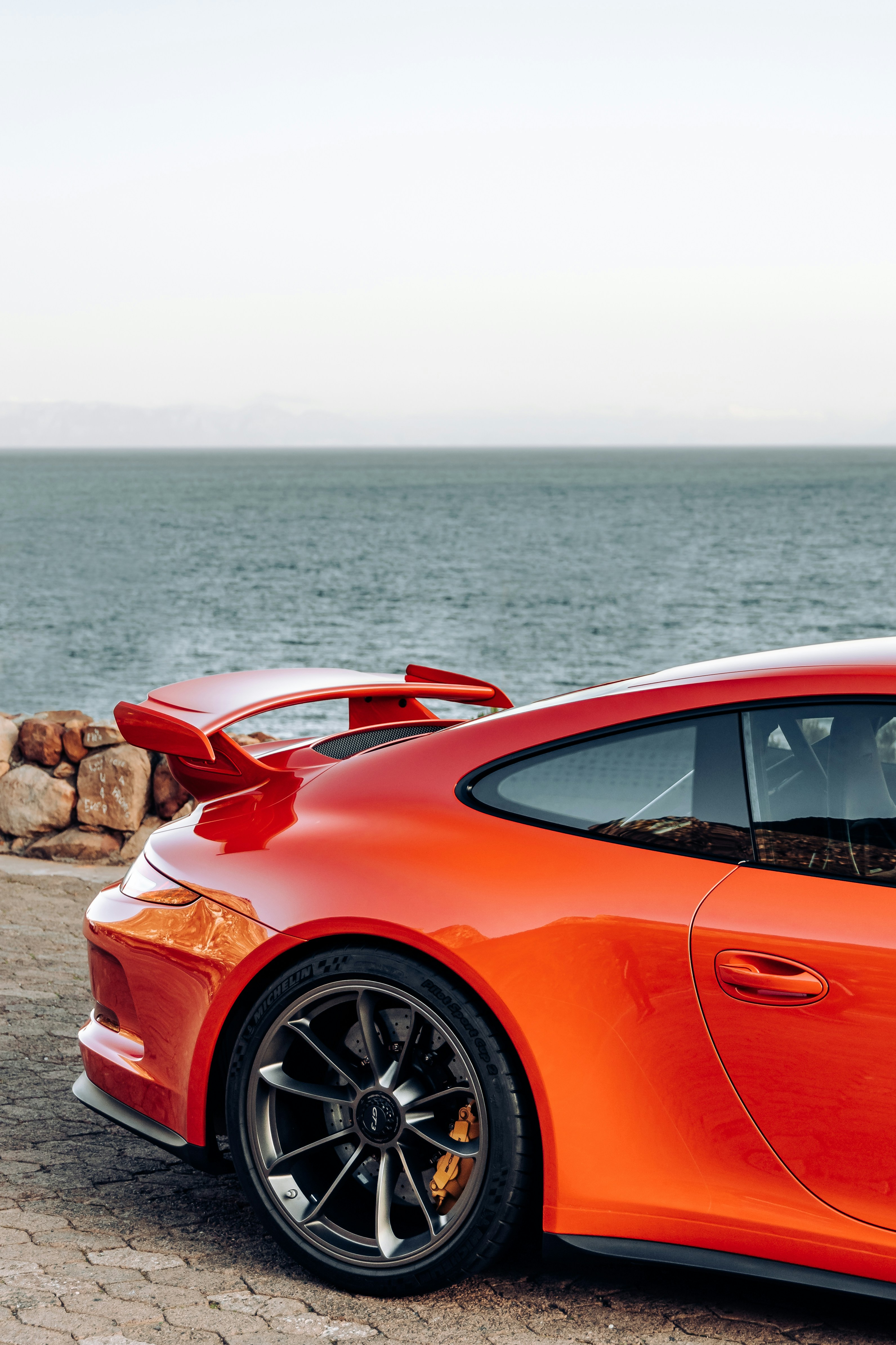 Scarlet Velocity by the Sea: A Porsche’s Rear Quarter Amid Coastal Light
