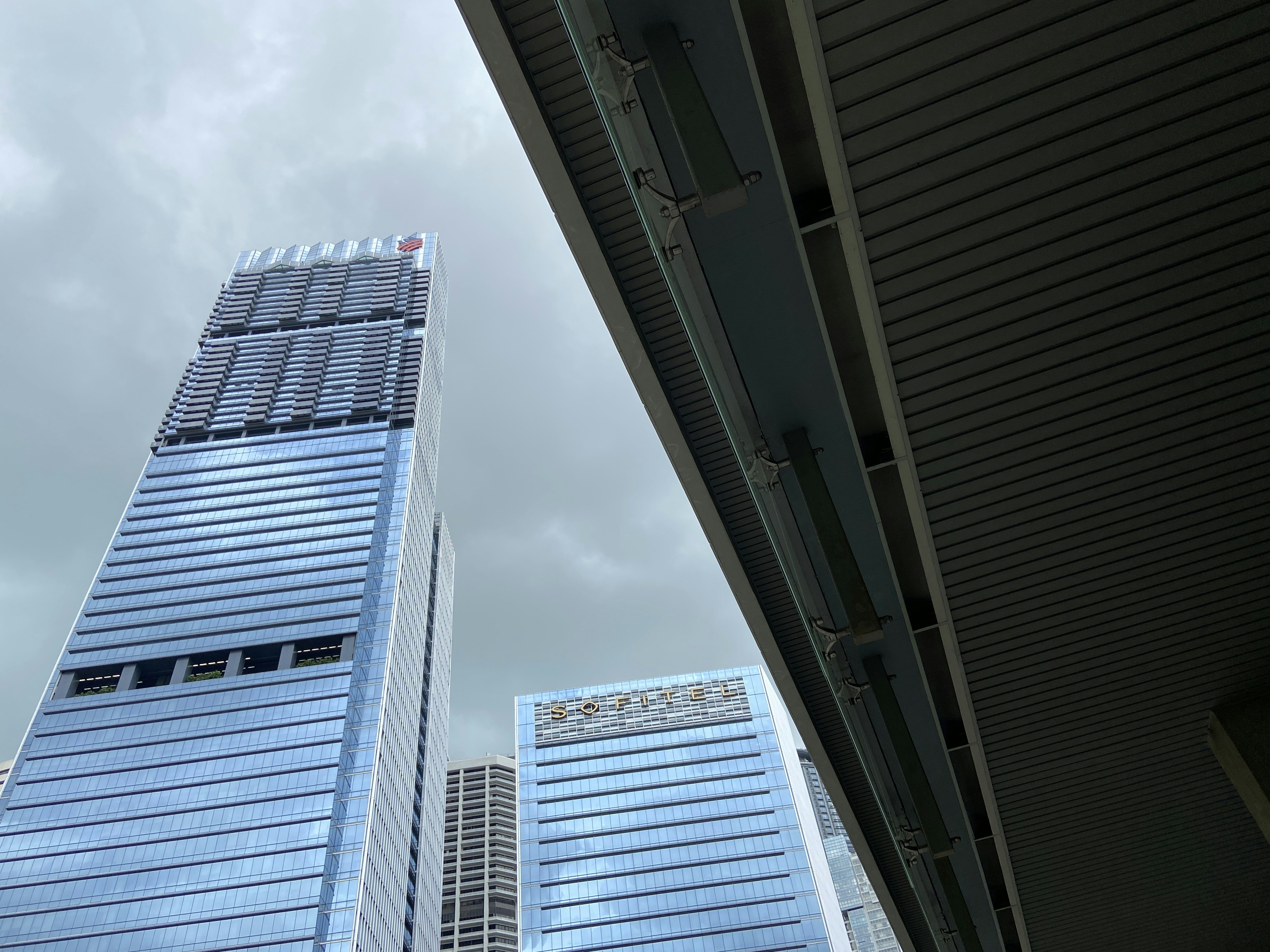 Skyscrapers with reflective glass facades under a moody sky, showcasing the interplay of architecture and nature.