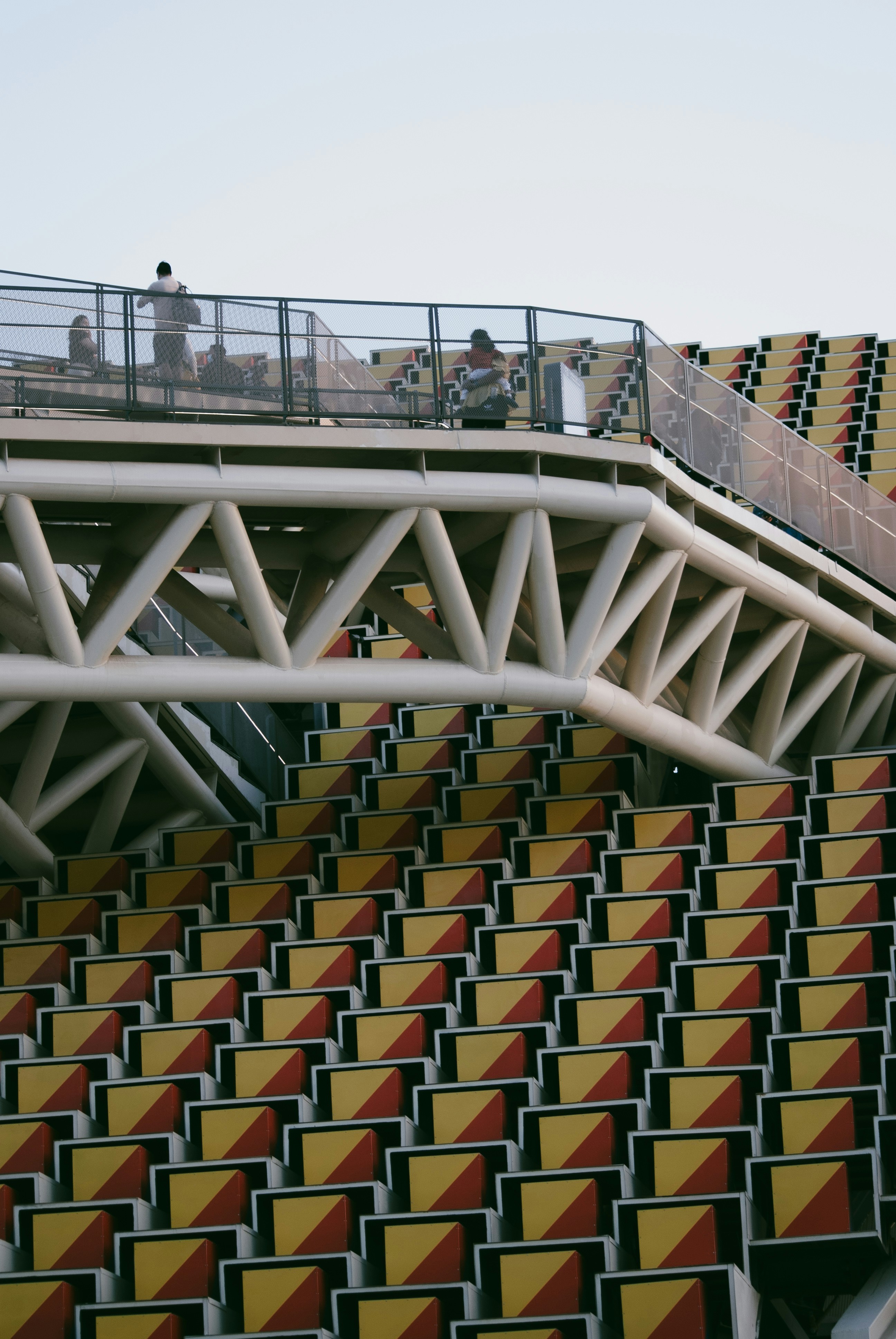 Colorful seating arrangement in a modern stadium structure, showcasing a blend of triangular patterns and vibrant hues.